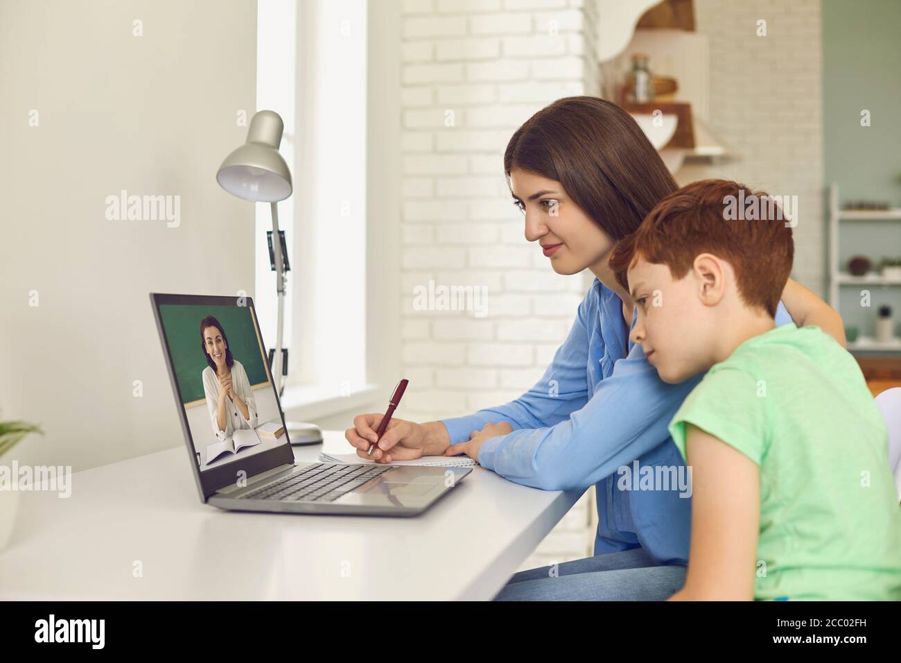 Mother and her son participating in online class at home. Parent and ...
