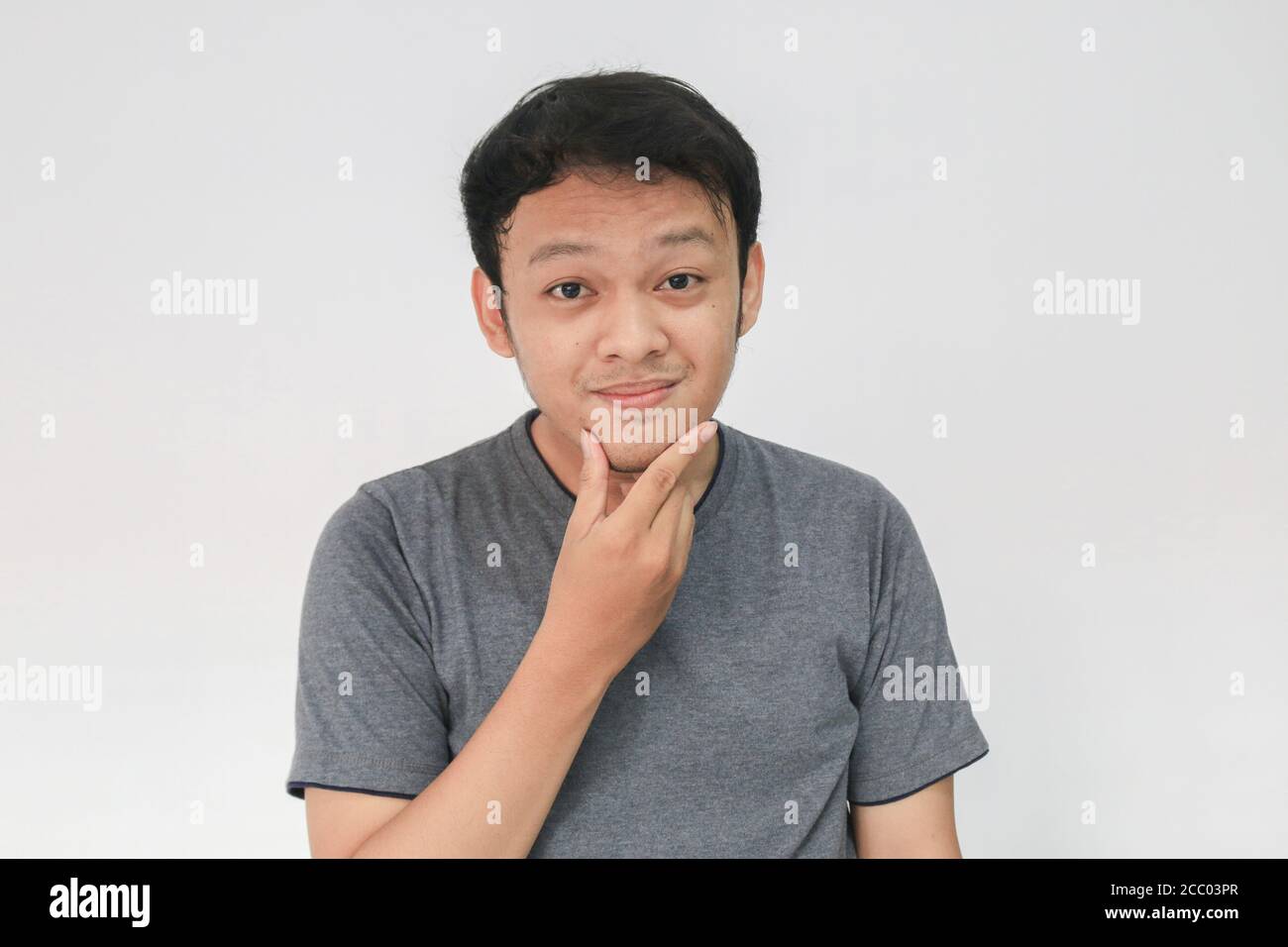 Funny tricky awkward face with hidden motive of Asian man in grey t ...