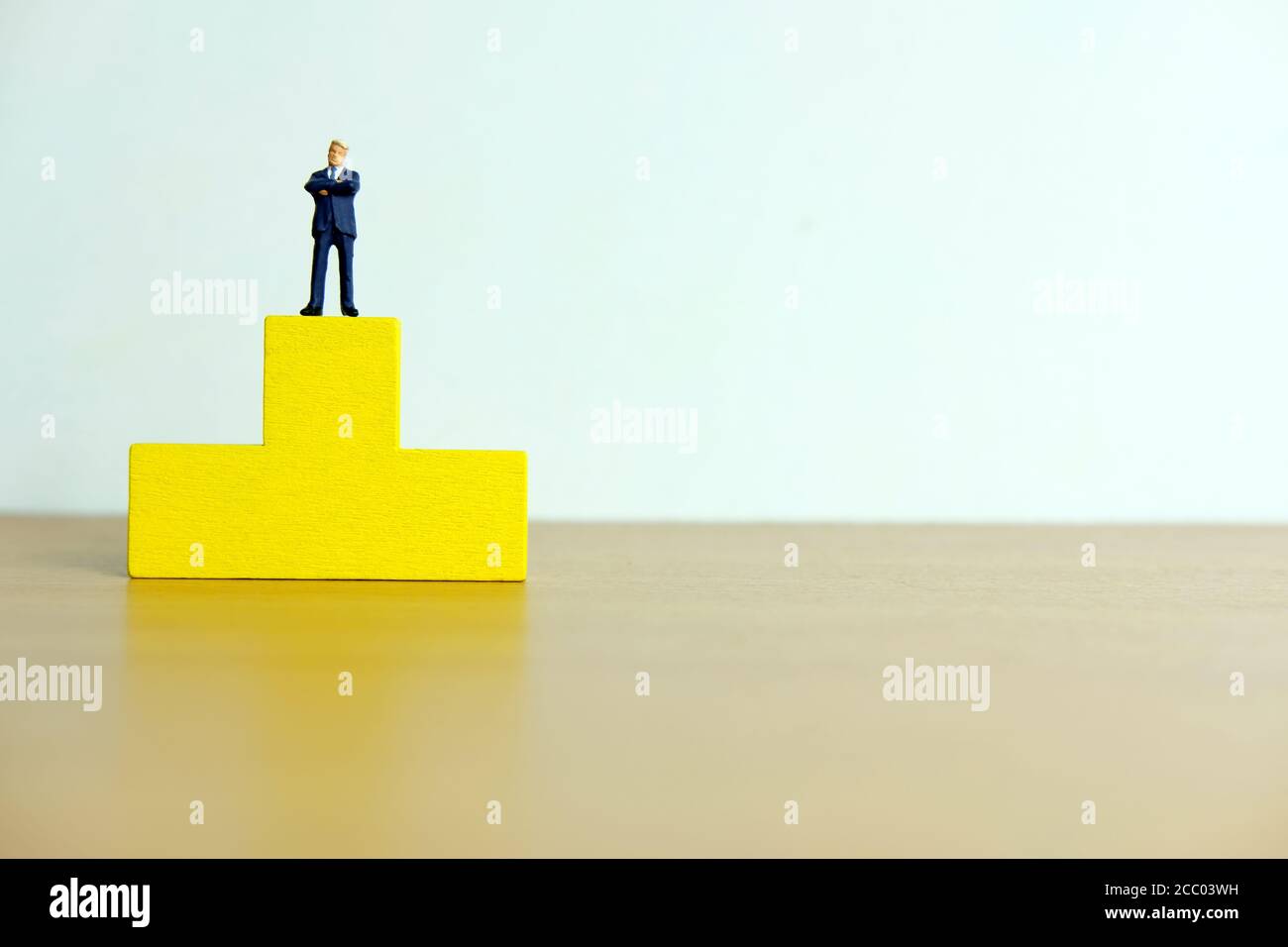 Miniature business concept - businessman standing on a podium to ...