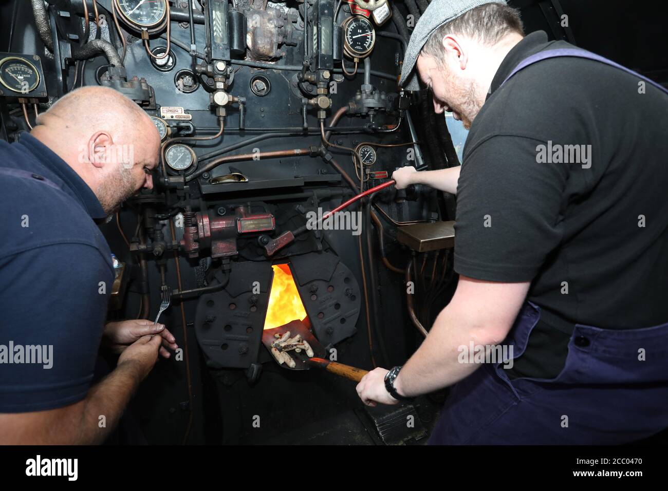 Paul Roe, left, and Jamie Bond cook sausages and bacon on the coal ...