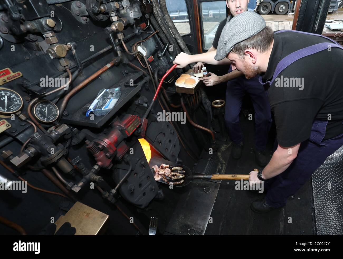 Paul Roe, left, and Jamie Bond cook sausages and bacon on the coal ...