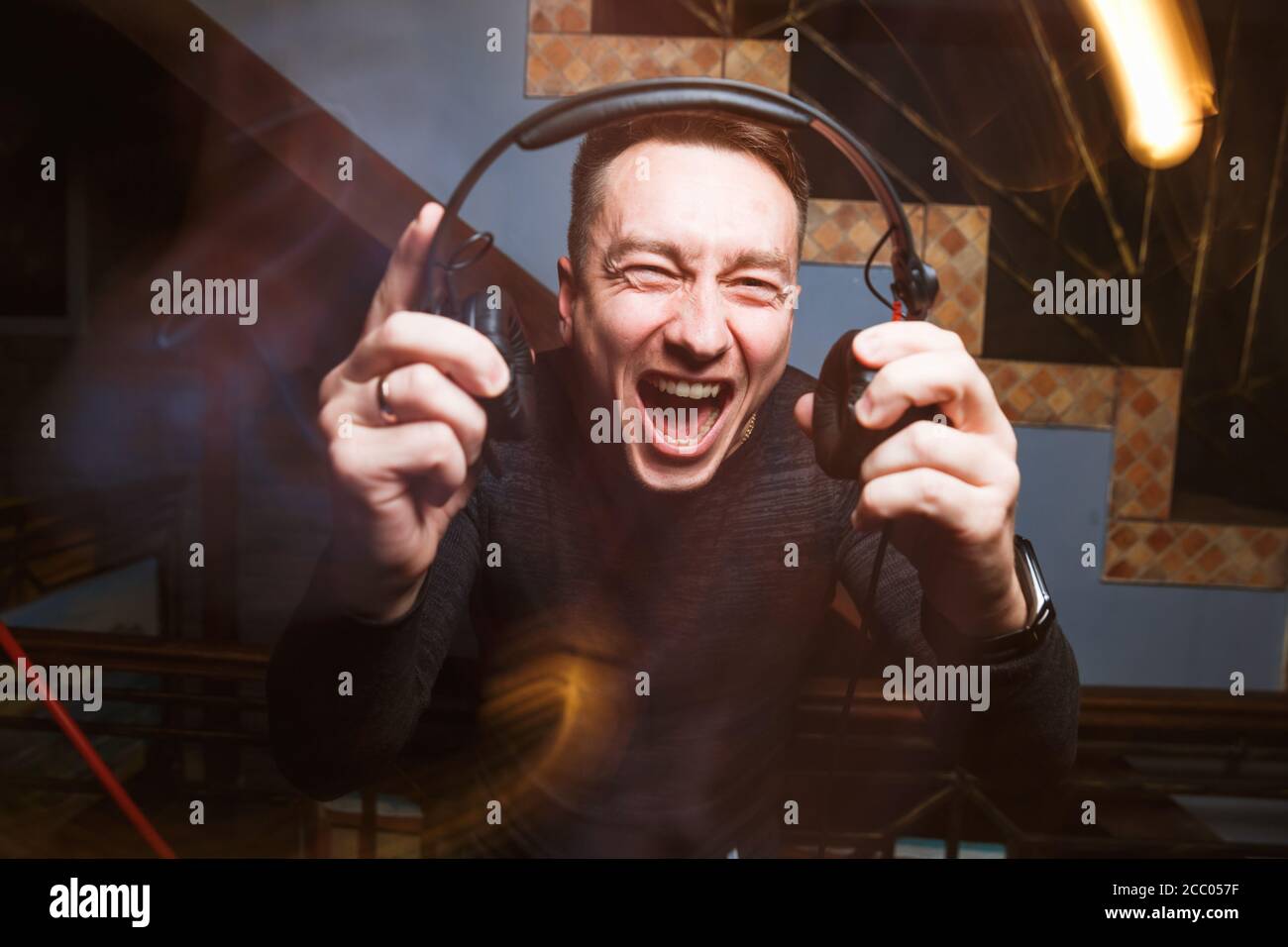 The face of a man with emotions. DJ puts on headphones. Young emotional ...