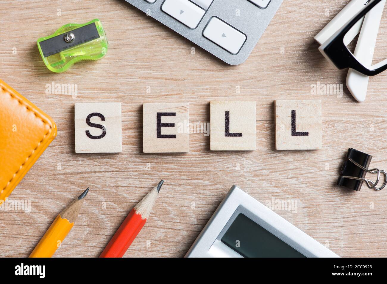 Office stuff and SELL word spelled with wooden blocks on workplace ...