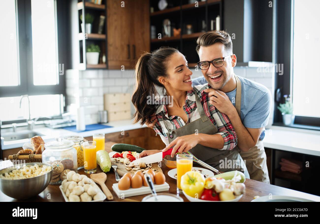 Beautiful couple is smiling while cooking together in the kitchen Stock ...