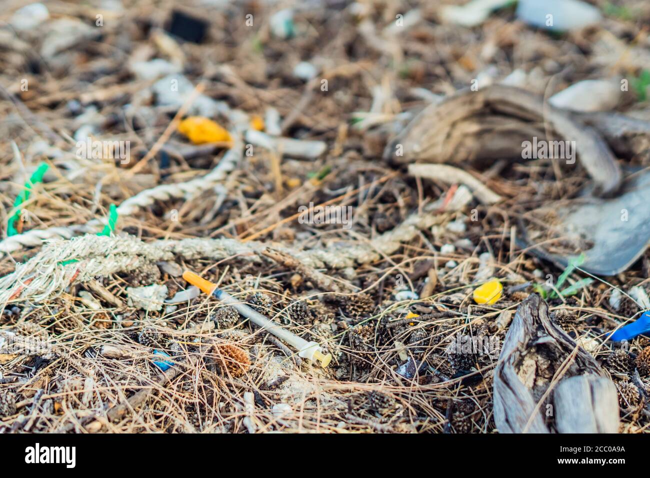 Spilled rubbish on the ground in the forest park. Ropes and plastic ...