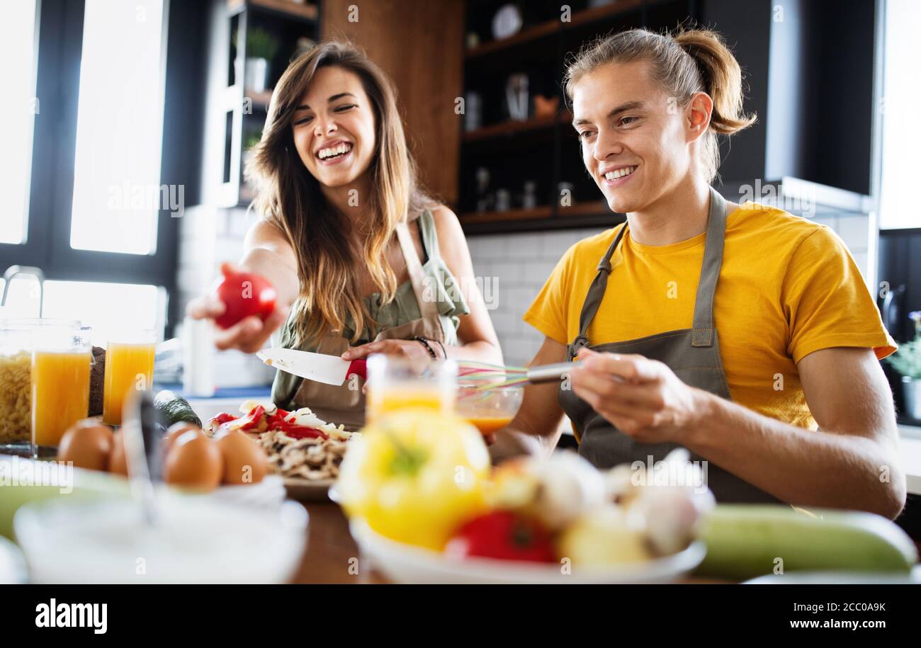 Beautiful couple is smiling while cooking together in the kitchen Stock ...