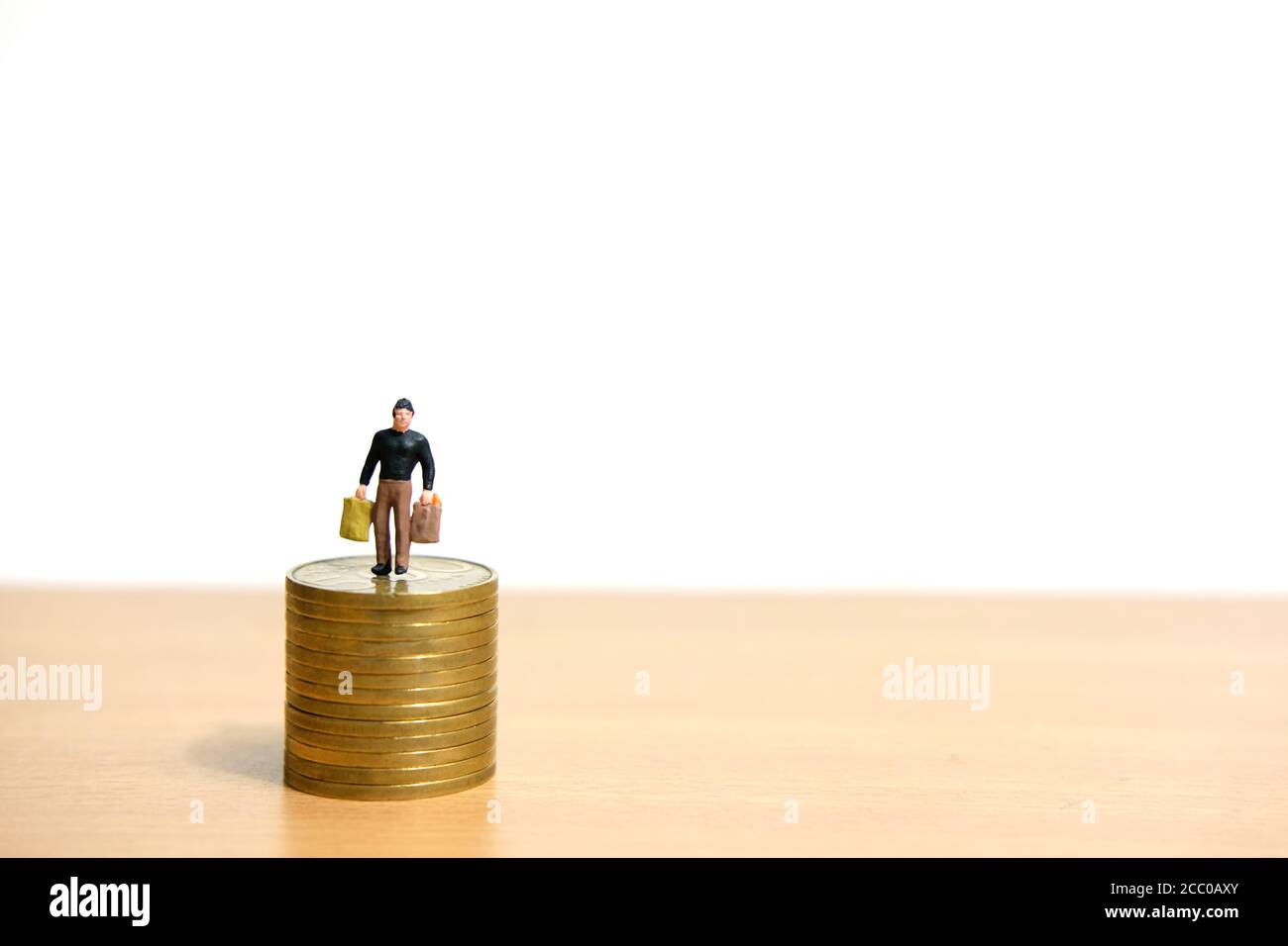 A man standing above coin stack to protect money. Miniature people ...