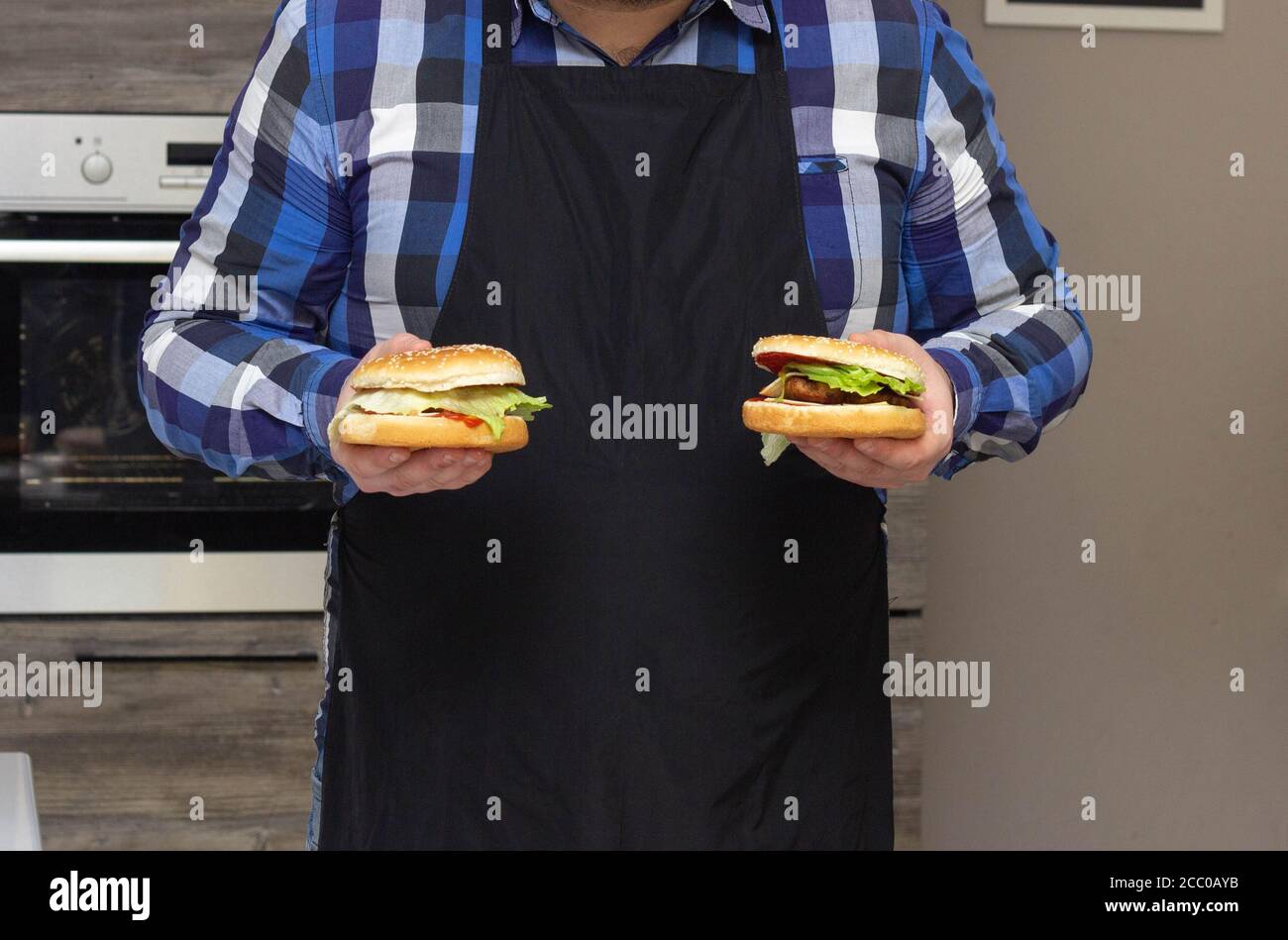 a man with a beard and in an apron holds burgers in his hands in the ...