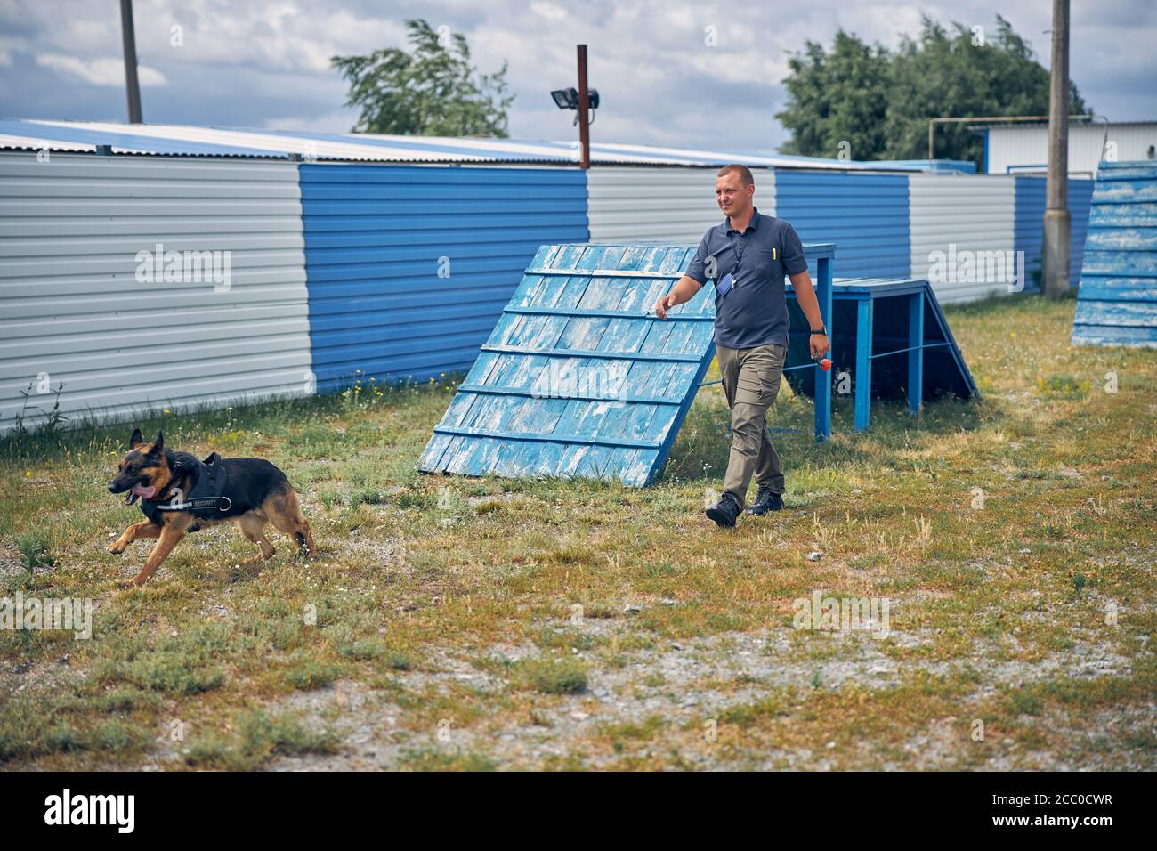 Male handler training German Shepherd dog on playground Stock Photo - Alamy