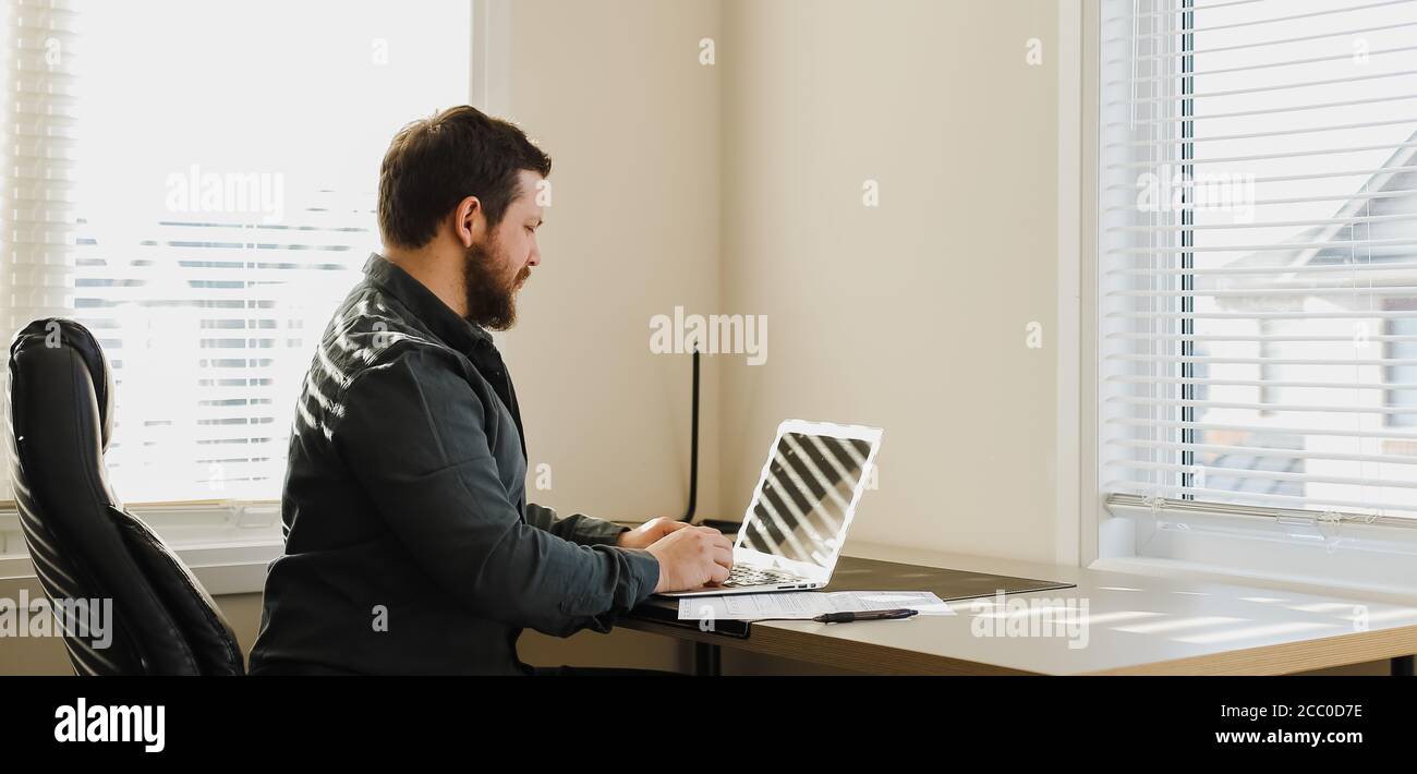 Male computer hakcer sitting at desk and using laptop at cabinet Stock ...