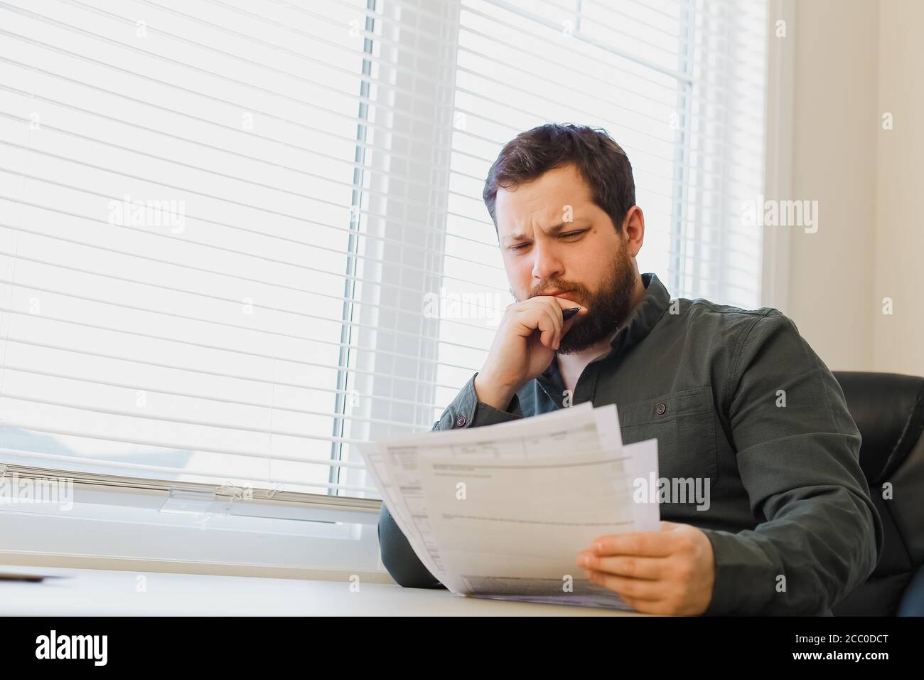 Businessman filling documents at cabinet, holding papers and pen Stock ...