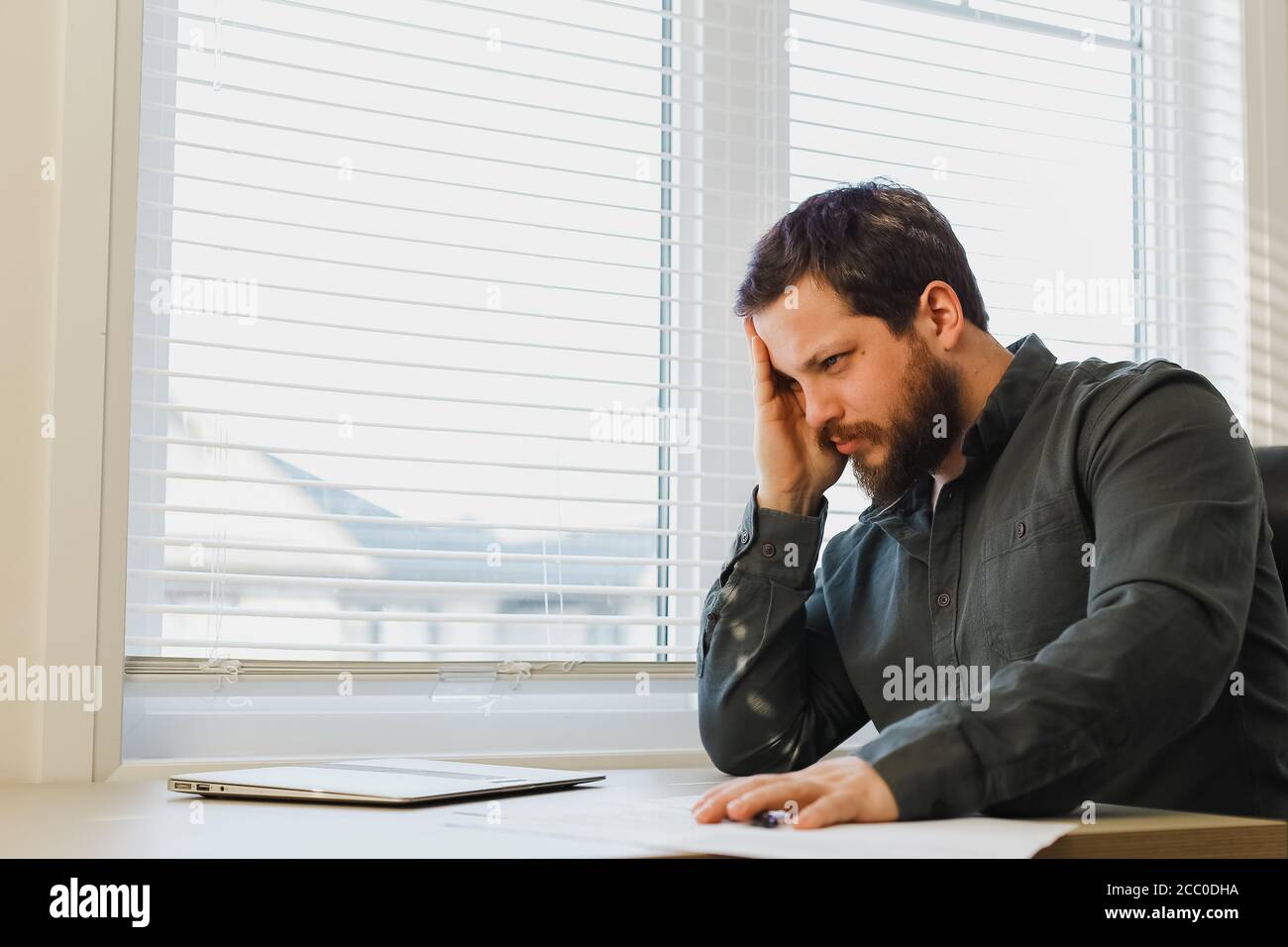 Tired thinking enterpreneur working with documents at office, closed ...