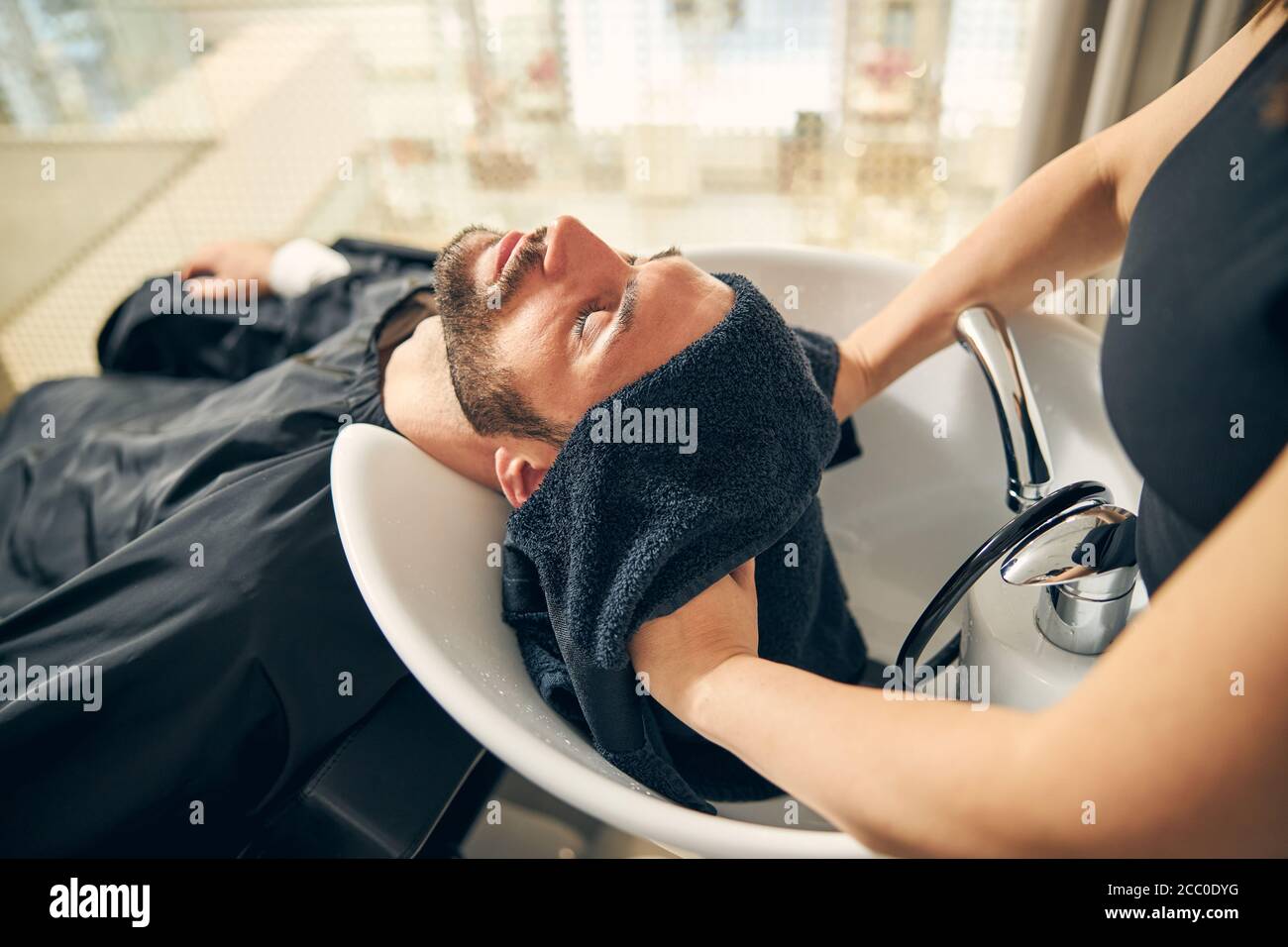Young female person wiping head of her client Stock Photo - Alamy