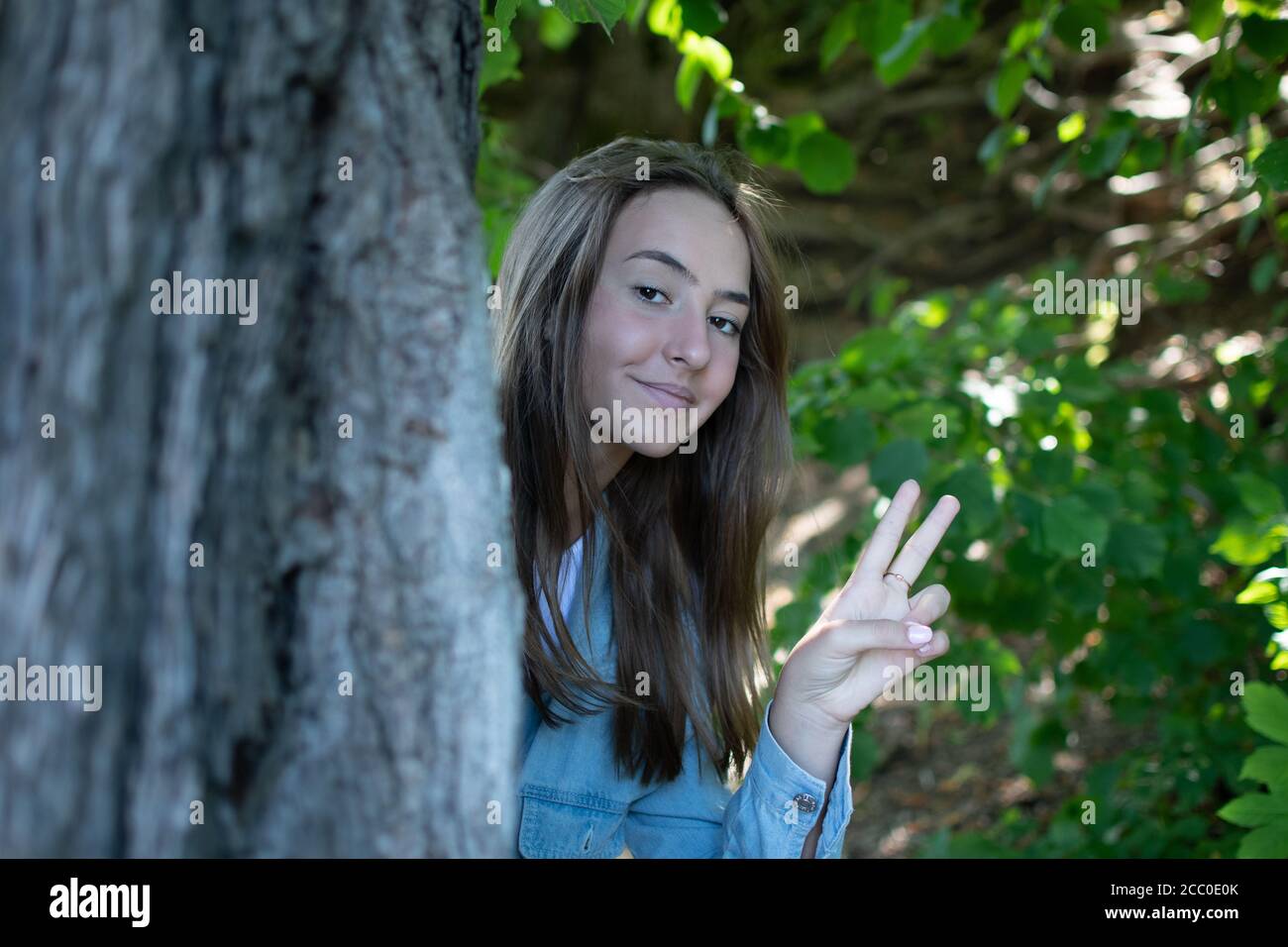 Beautiful girl making victory gesture in nature Stock Photo - Alamy