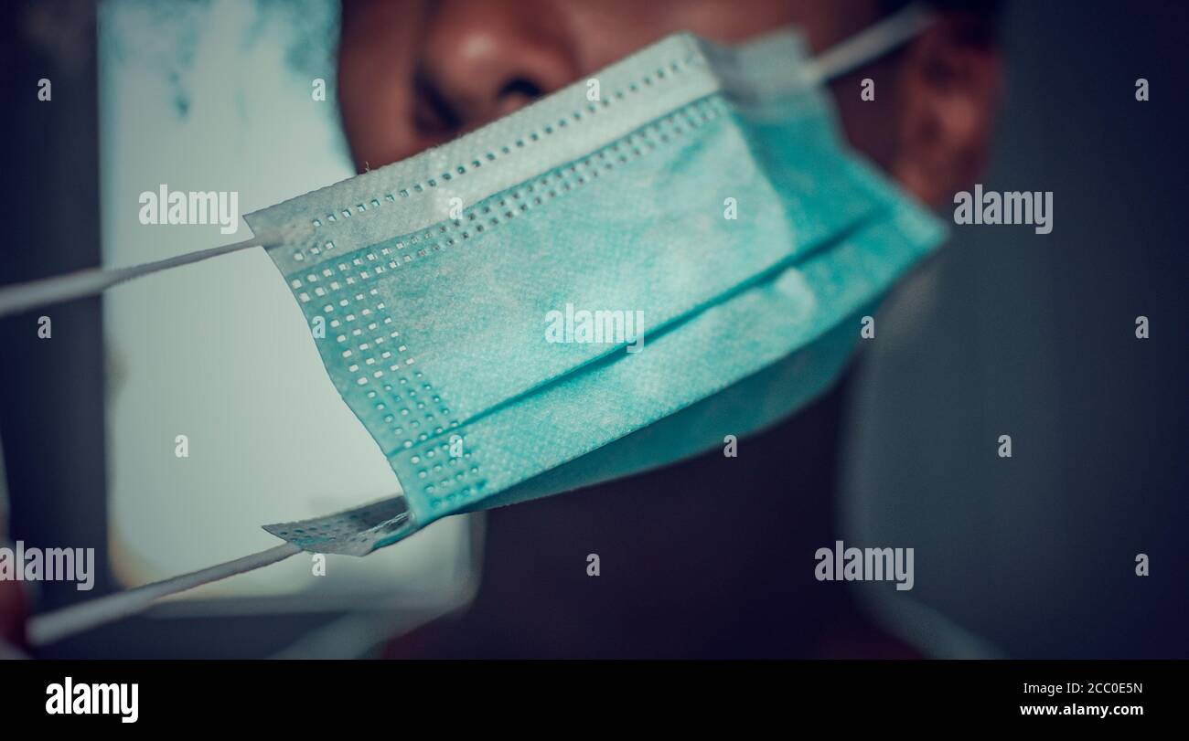 Black woman putting on or taking off her face mask. Selective focus on ...