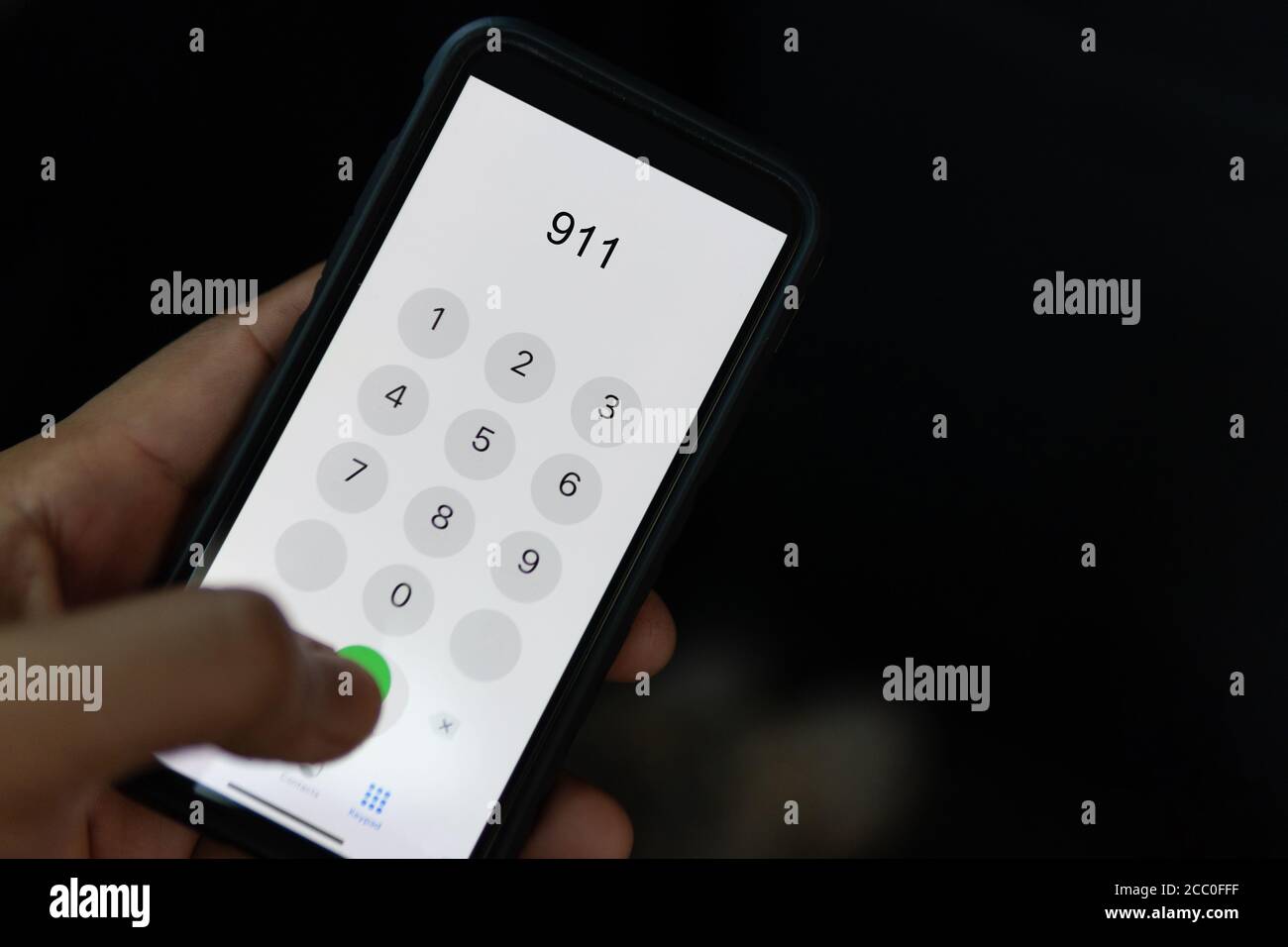 Hand holding cell phone with emergency number 911 on black background ...