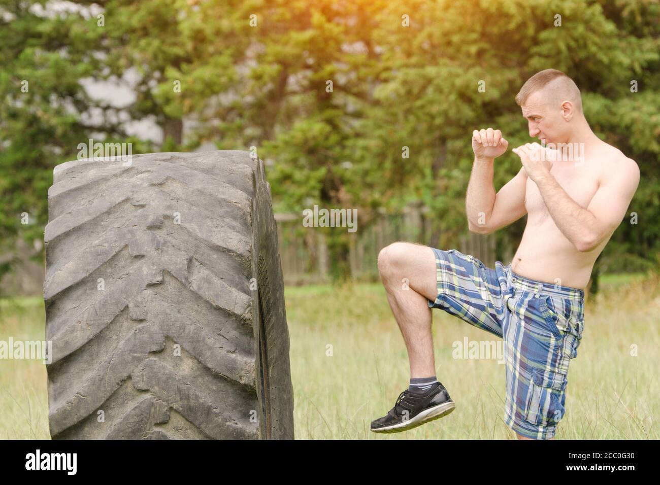 Young man boxing with the tire. Workout Stock Photo - Alamy