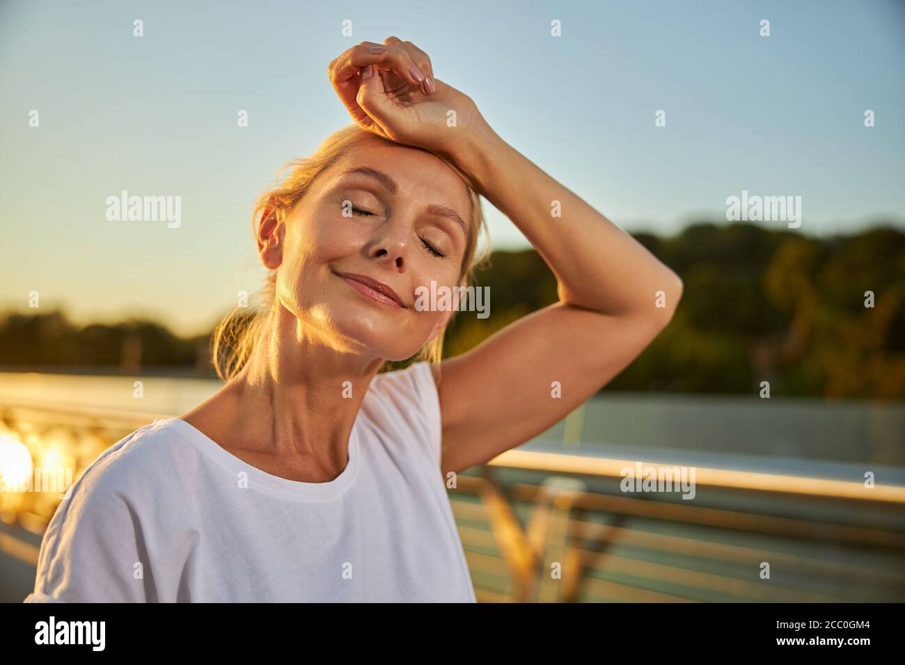 Beautiful serene woman placing hand on her forehead Stock Photo - Alamy