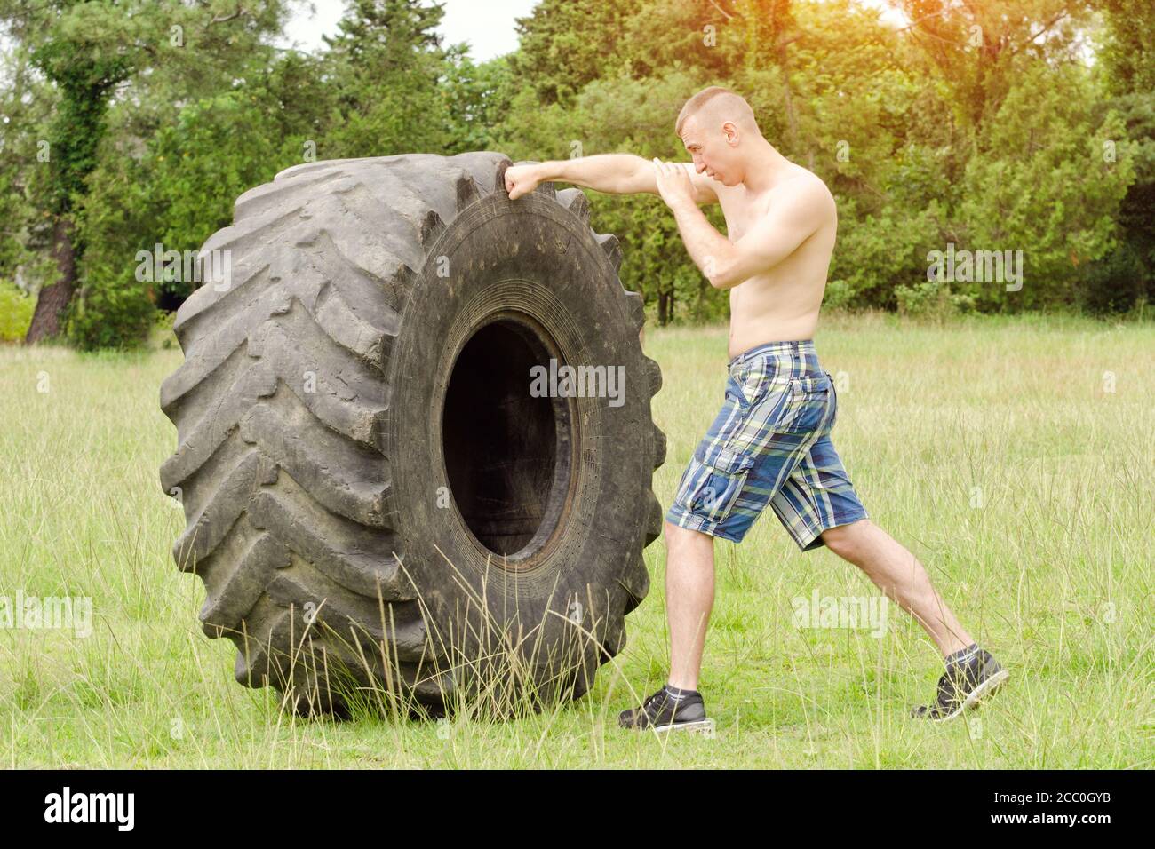 Young man boxing with the tire. Workout Stock Photo - Alamy