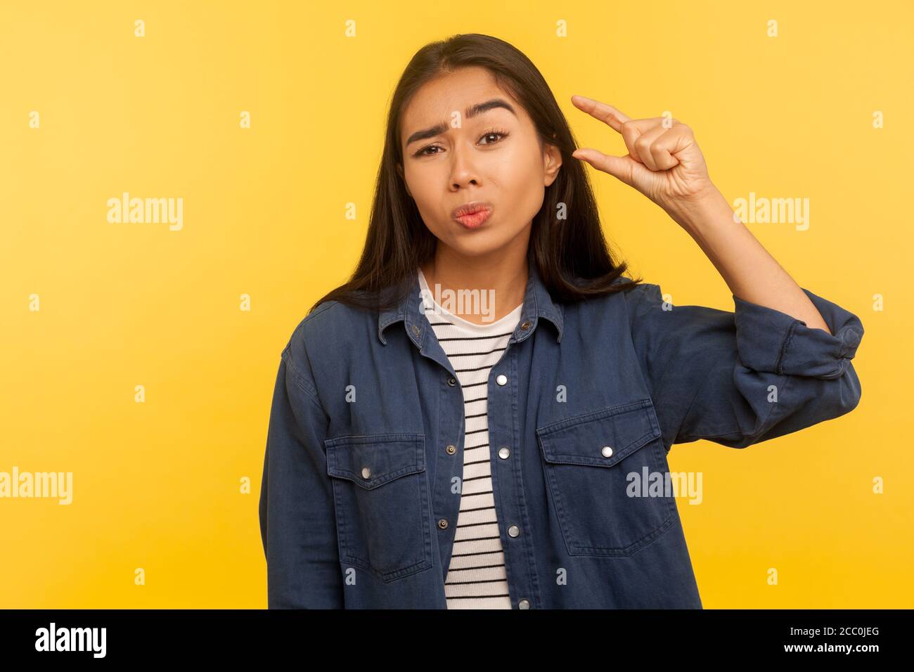 Too small! Portrait of displeased girl in denim shirt showing a little ...