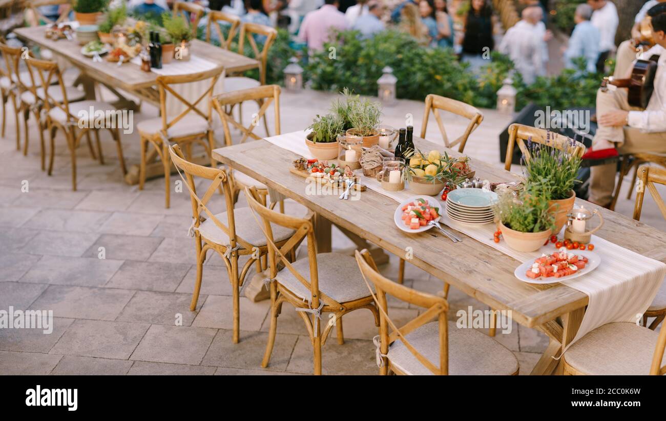 Festively decorated tables with live flowers in pots in nature. A ...