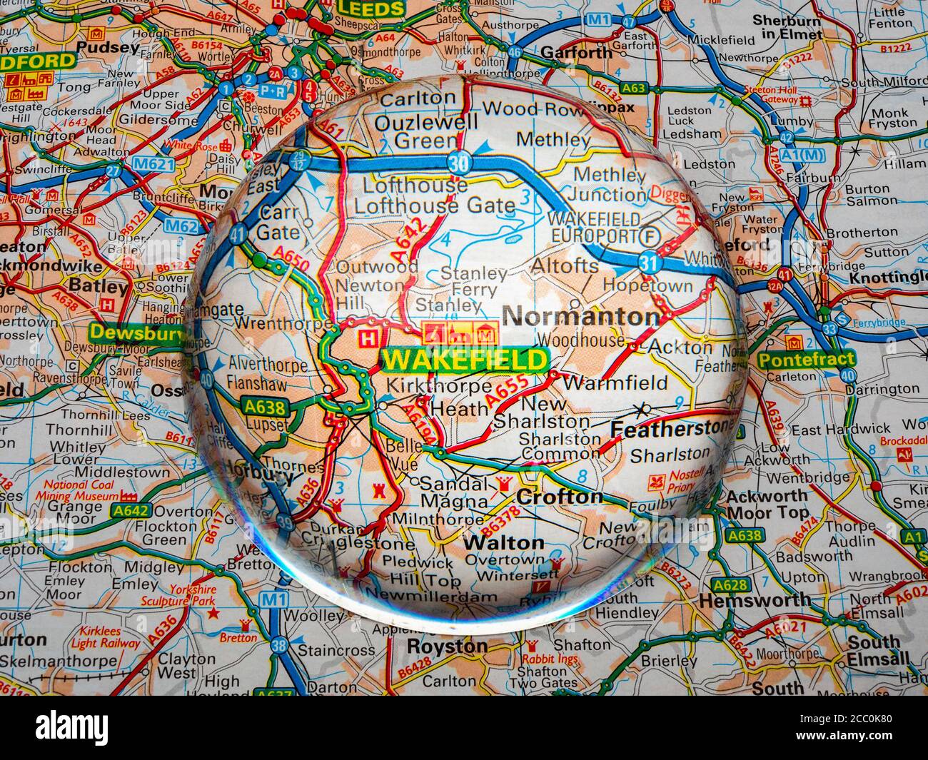 Closeup of a dome shaped magnifying glass over a page of a British road ...