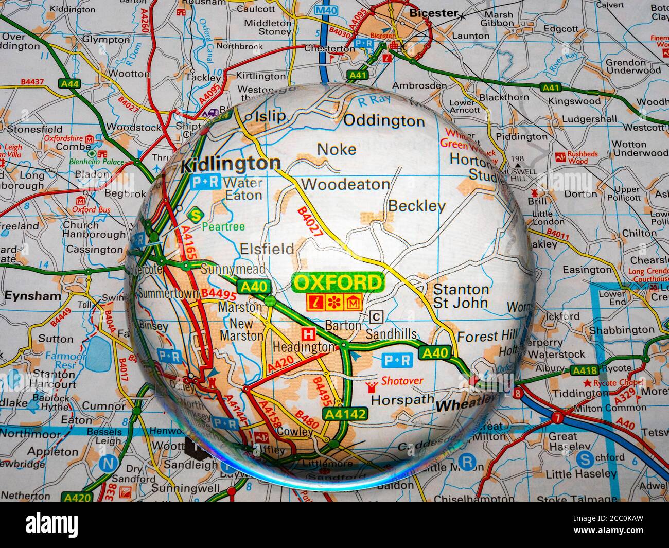 Closeup of a dome shaped magnifying glass over a page of a British road ...