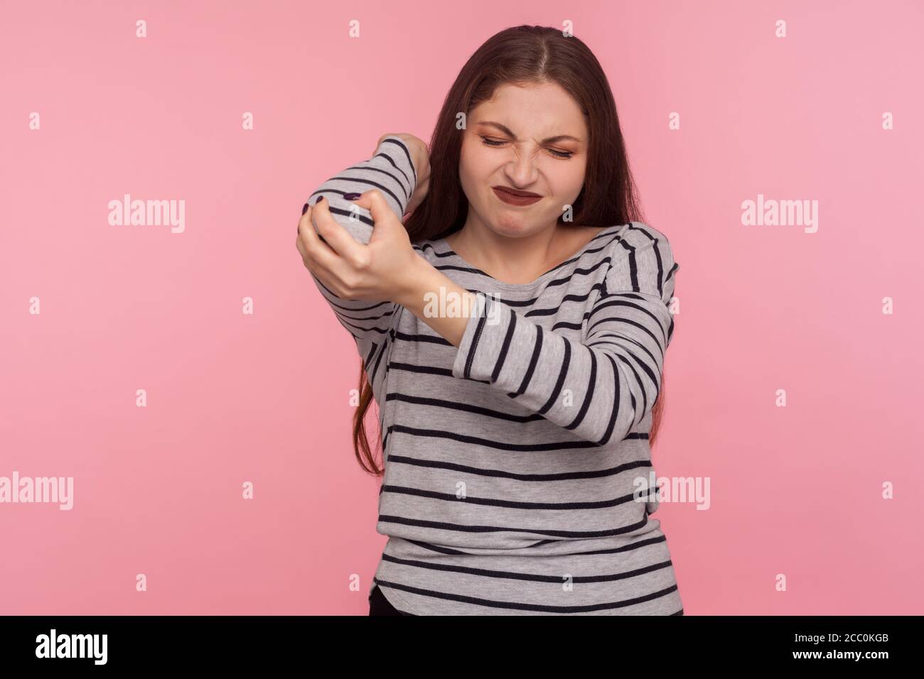 Hand injury. Portrait of woman massaging aching elbow, frowning from ...