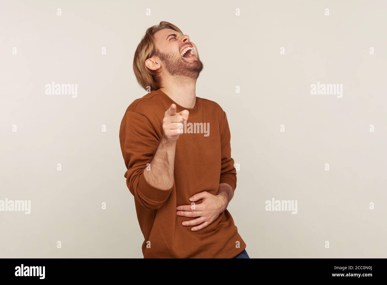 Hey you! Portrait of amused man with beard in sweatshirt holding hand ...