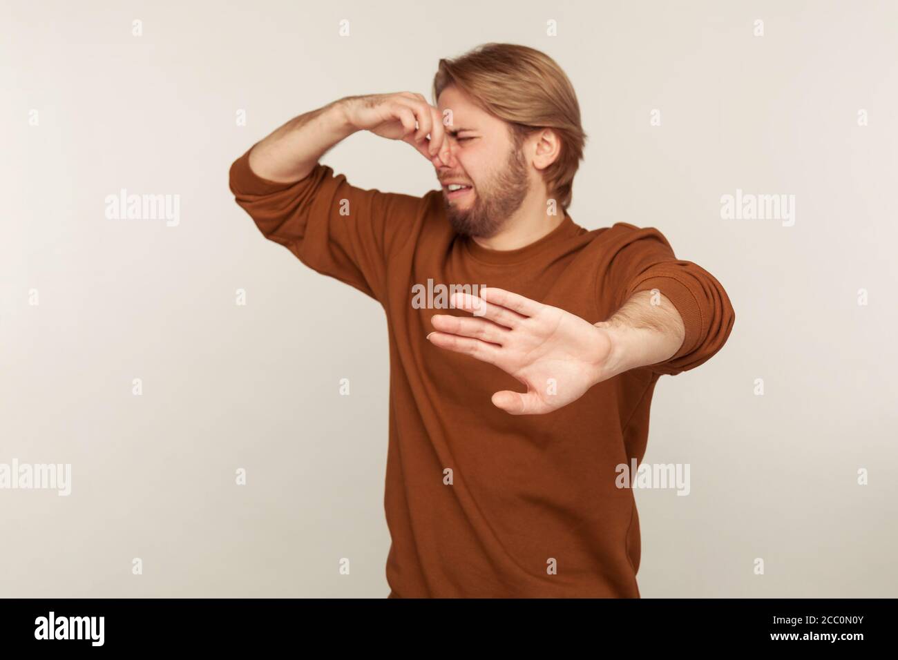Bad smell. Portrait of confused bearded man grabbing nose, grimacing in ...