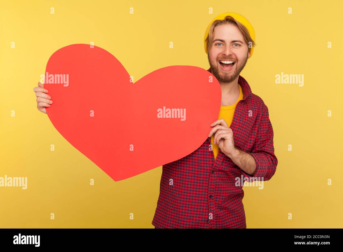 Handsome romantic guy holding big read heart and smiling at camera ...