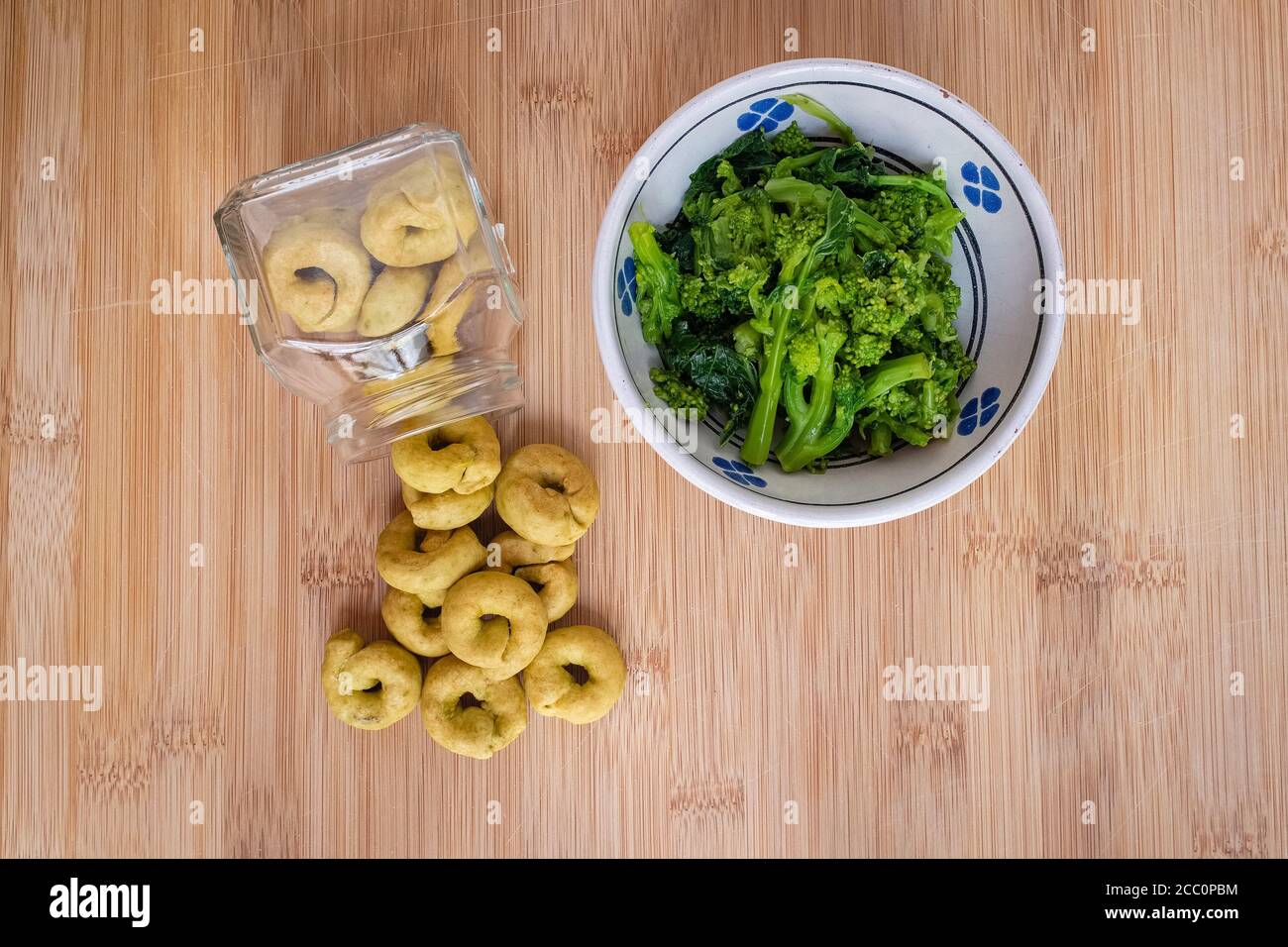Homemade rapini flavour taralli crackers poured from a glass jar next ...