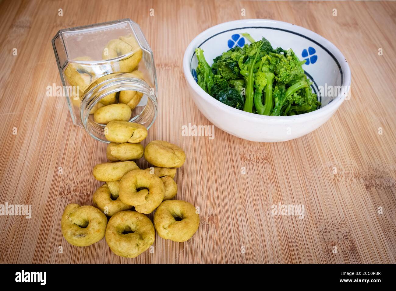 Homemade rapini flavour taralli crackers poured from a glass jar next ...