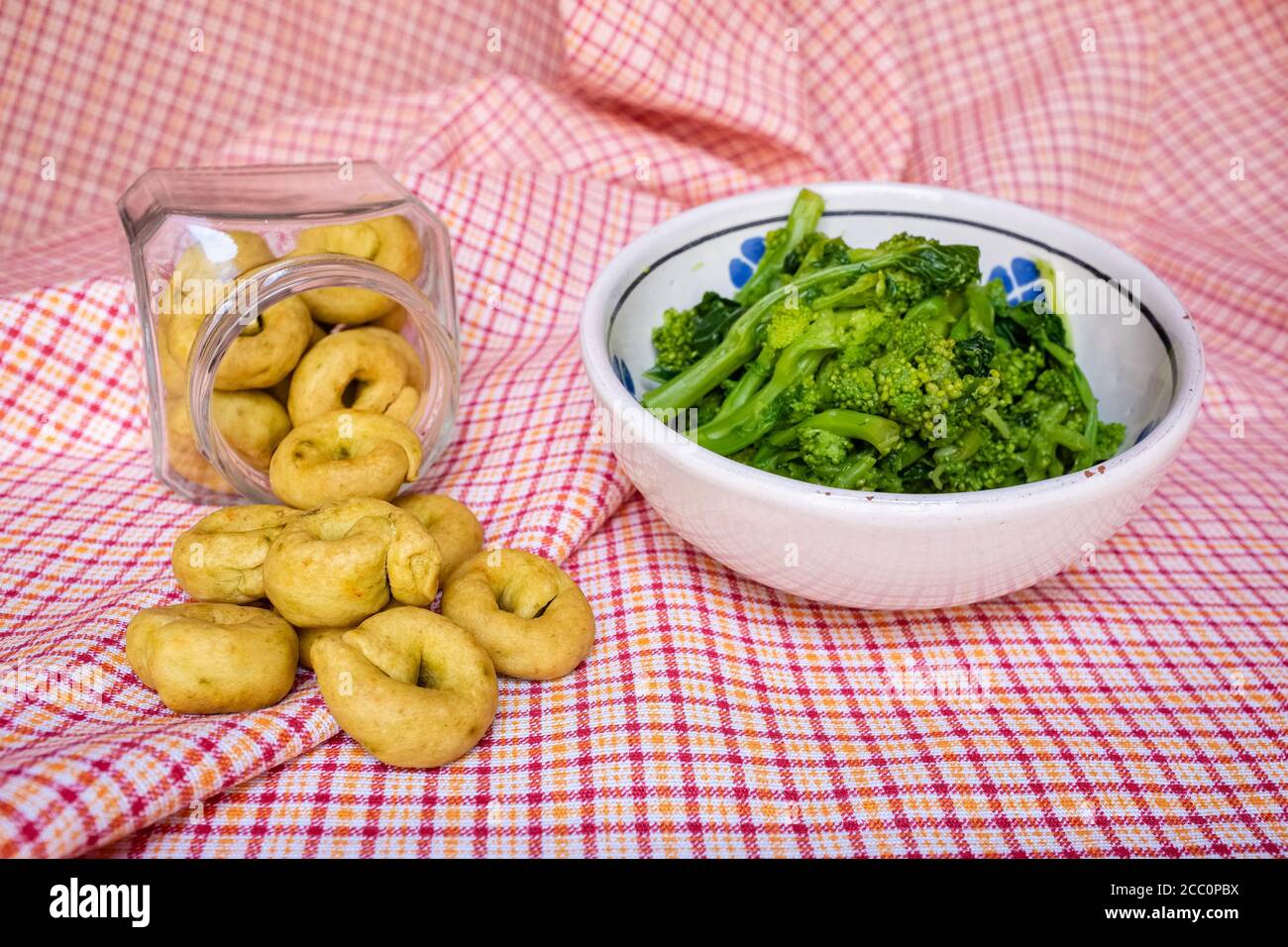 Homemade rapini flavour taralli crackers poured from a glass jar next ...