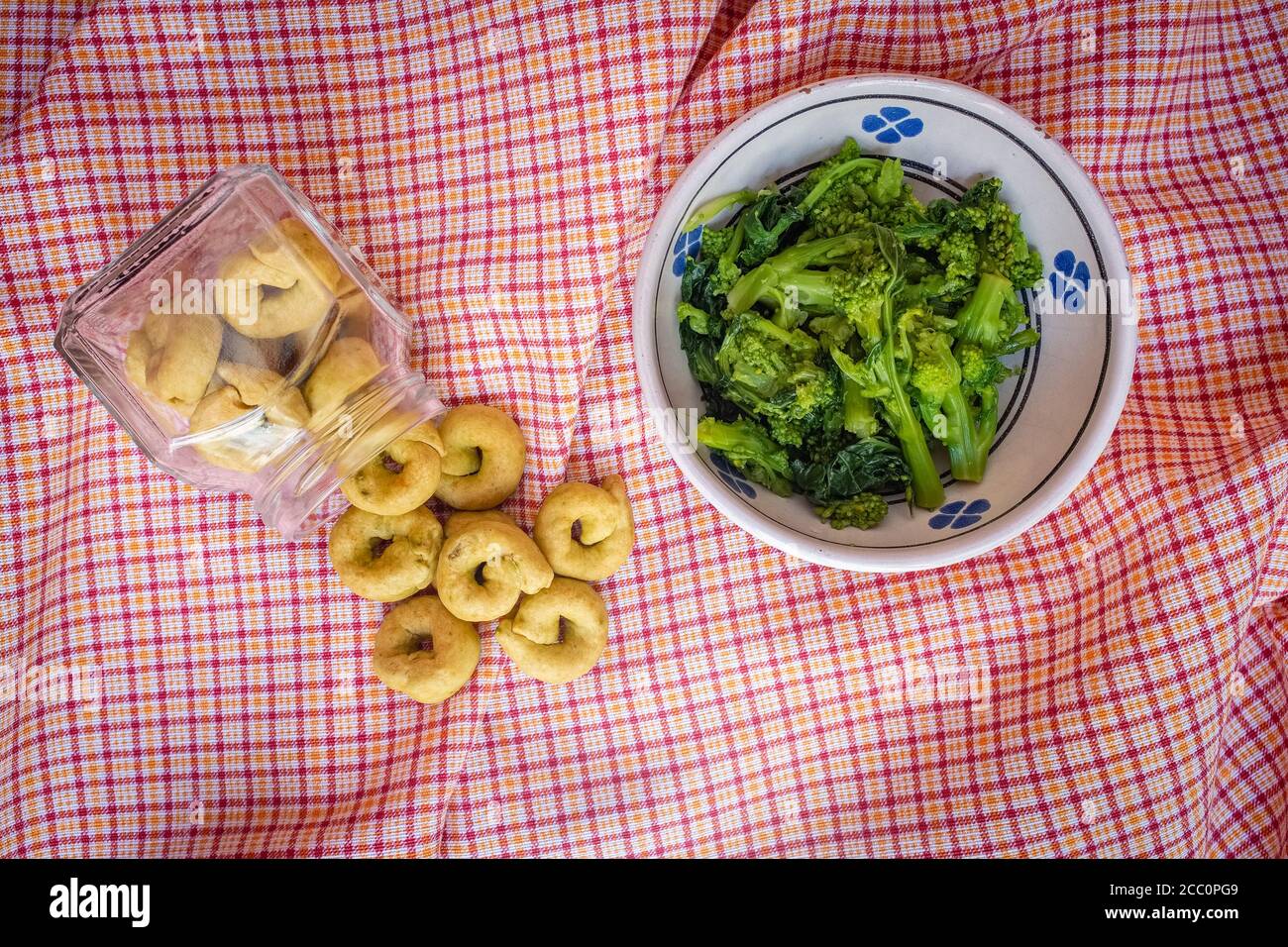 Homemade rapini flavour taralli crackers poured from a glass jar next ...