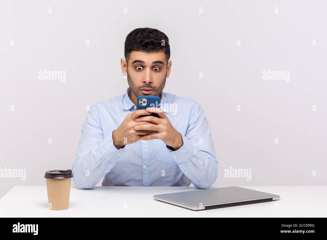 Amazed businessman sitting in office workplace reading shocking message ...
