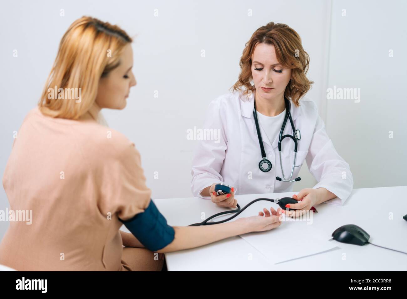 Professional female doctor measuring young woman patient pulse pressure ...
