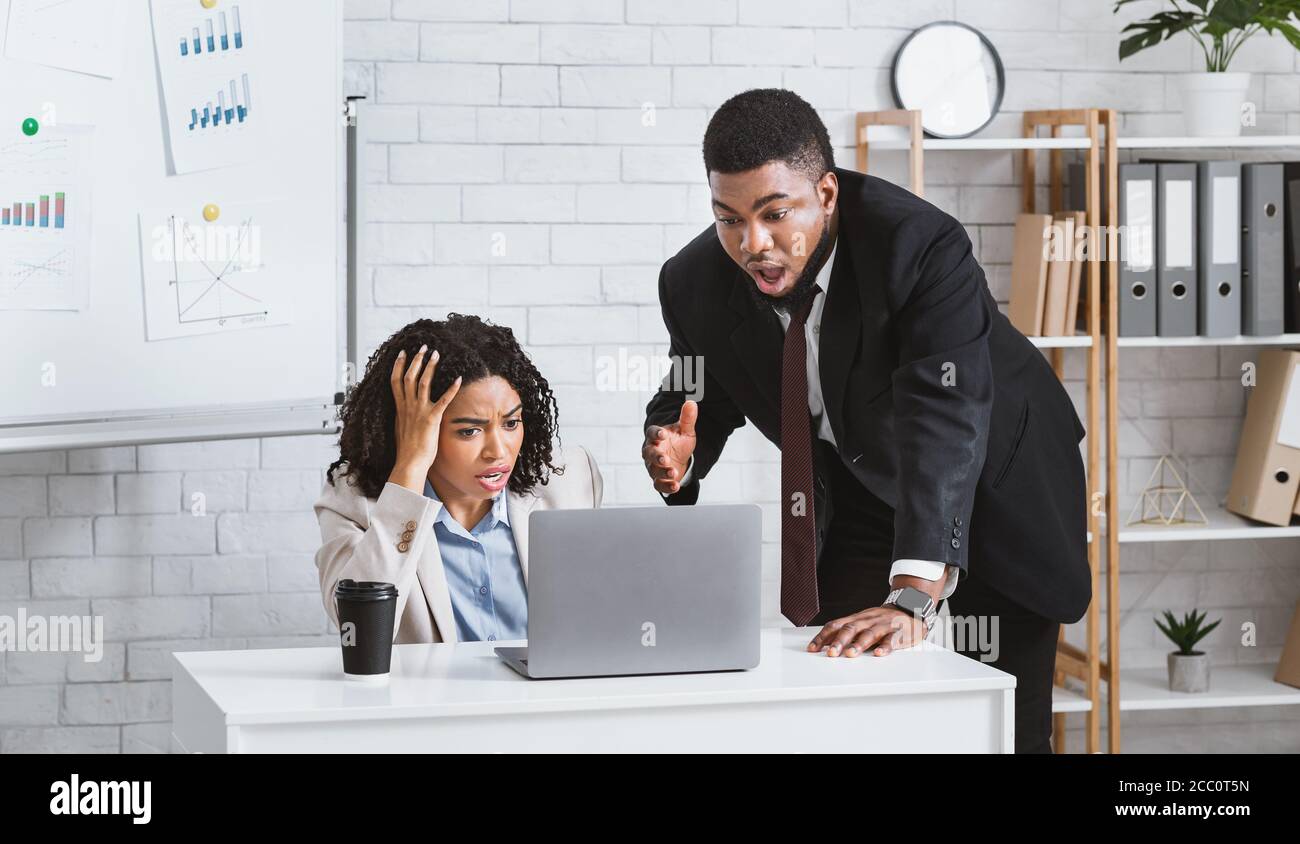 Stressed black woman with her male colleague finding error in work task ...