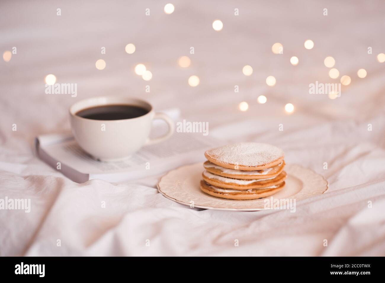 Stack of creamy pancakes with open book and fresh coffee over glowing ...