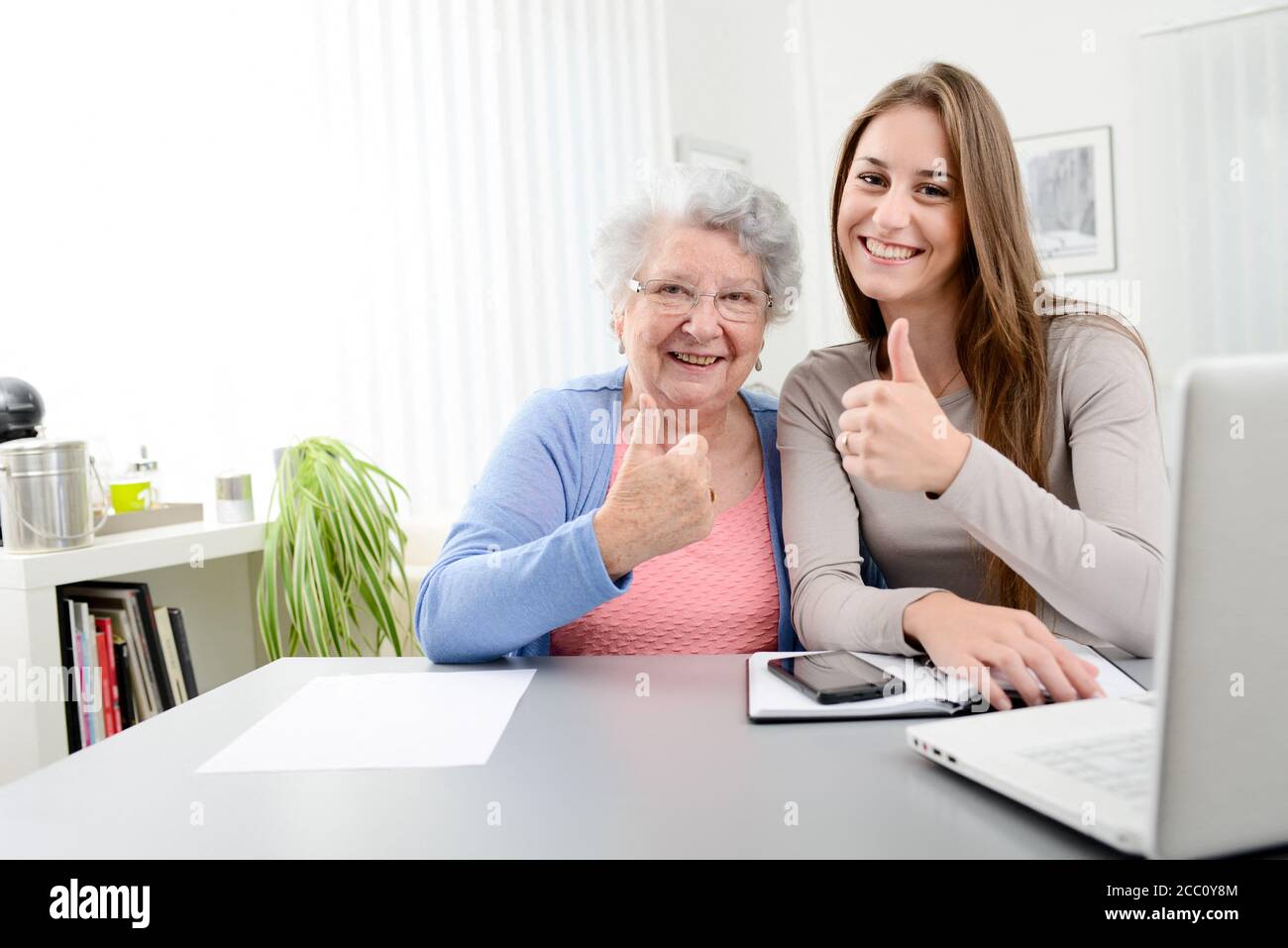 Young woman helping old senior woman doing paperwork and administrative ...