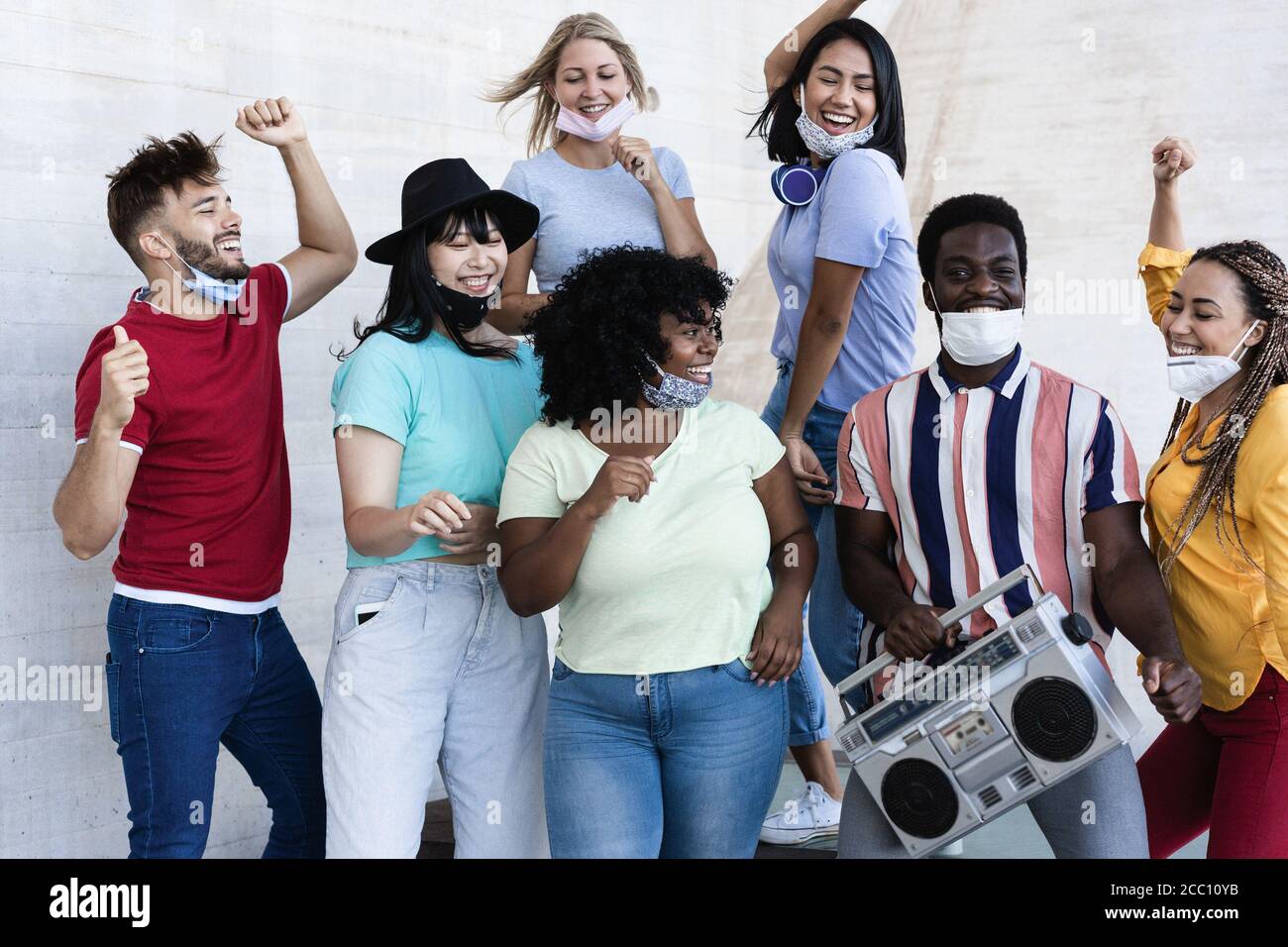 Happy people from different races dancing outdoor while listening music ...
