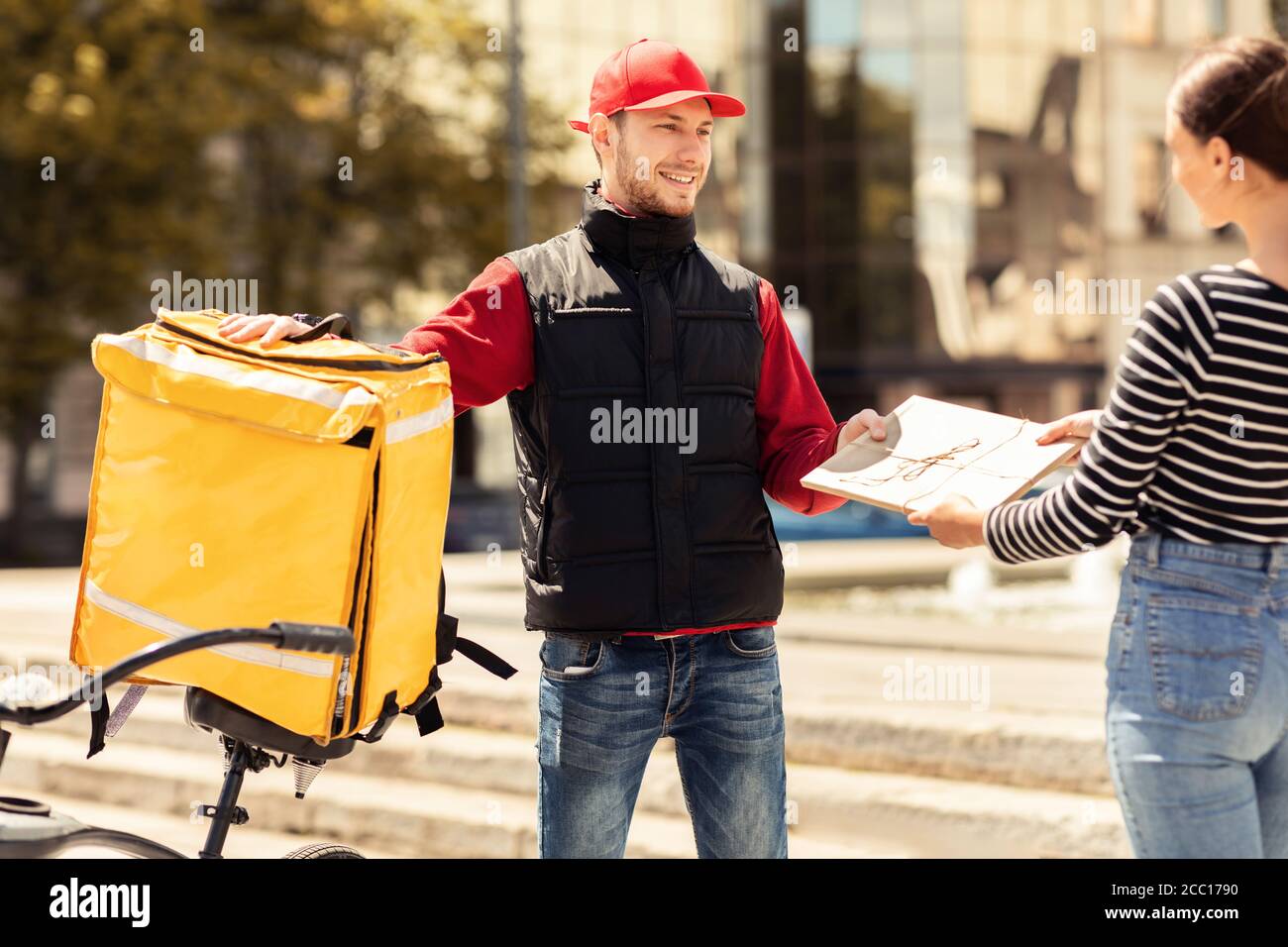 Guy Giving Package To Customer Girl Standing In Urban Area Stock Photo ...
