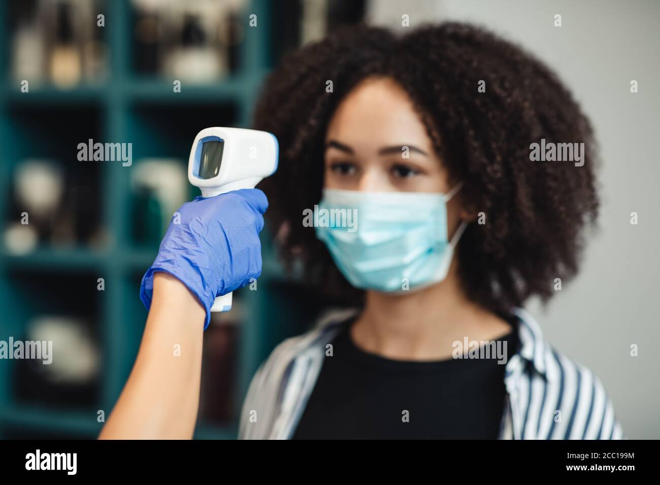 Black woman getting temperature screening with infrared thermometer ...