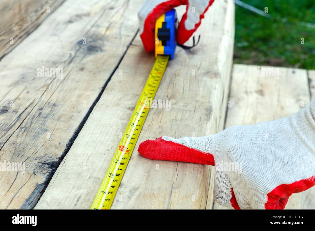 A male hand in work gloves points with the index finger to the length ...