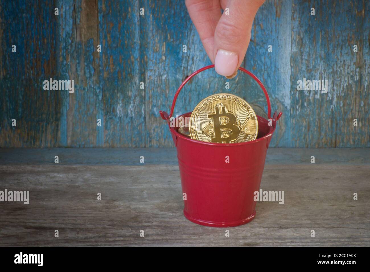 Pot with golden coin bitcoin in female hand. Old wooden background ...