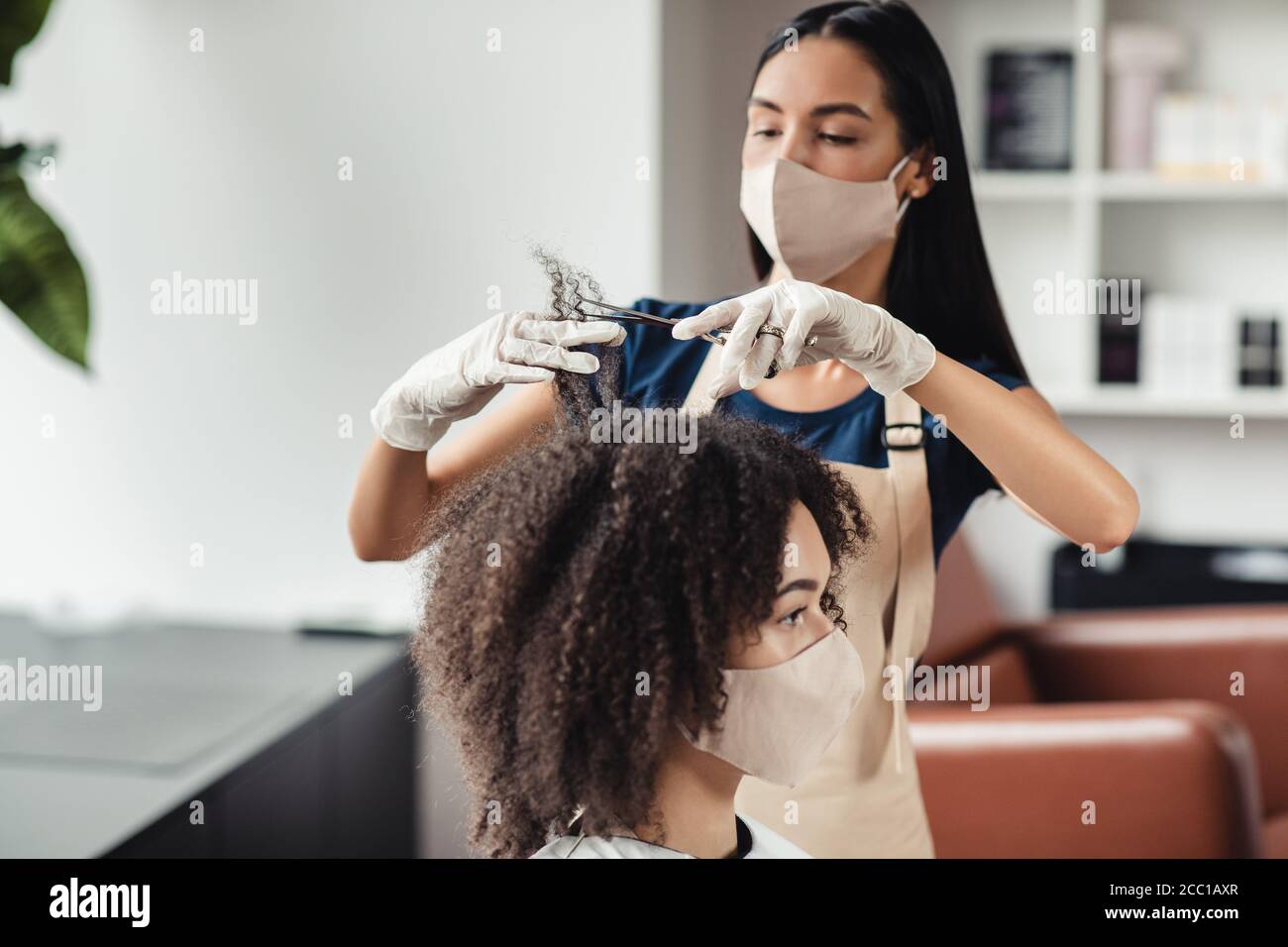 Black woman in protective mask visiting hairdresser at beauty salon ...