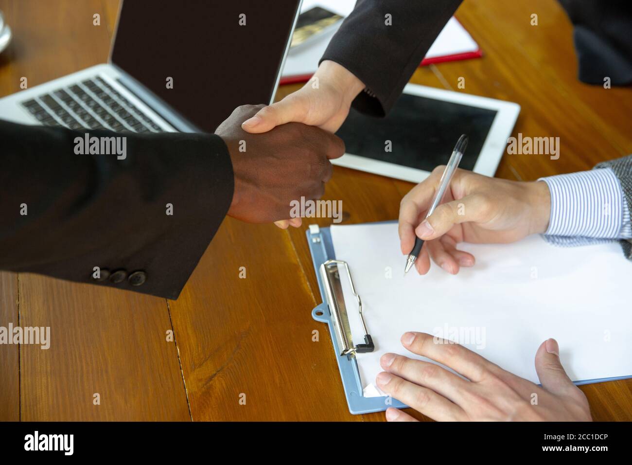 Close up of businessman and woman shaking hands in conference room ...