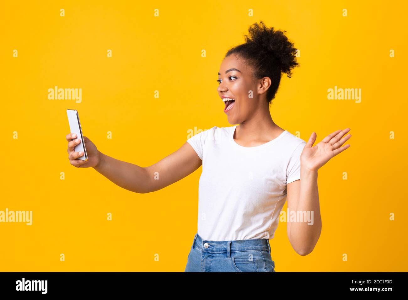 Happy girl using mobile phone for video call at studio Stock Photo - Alamy