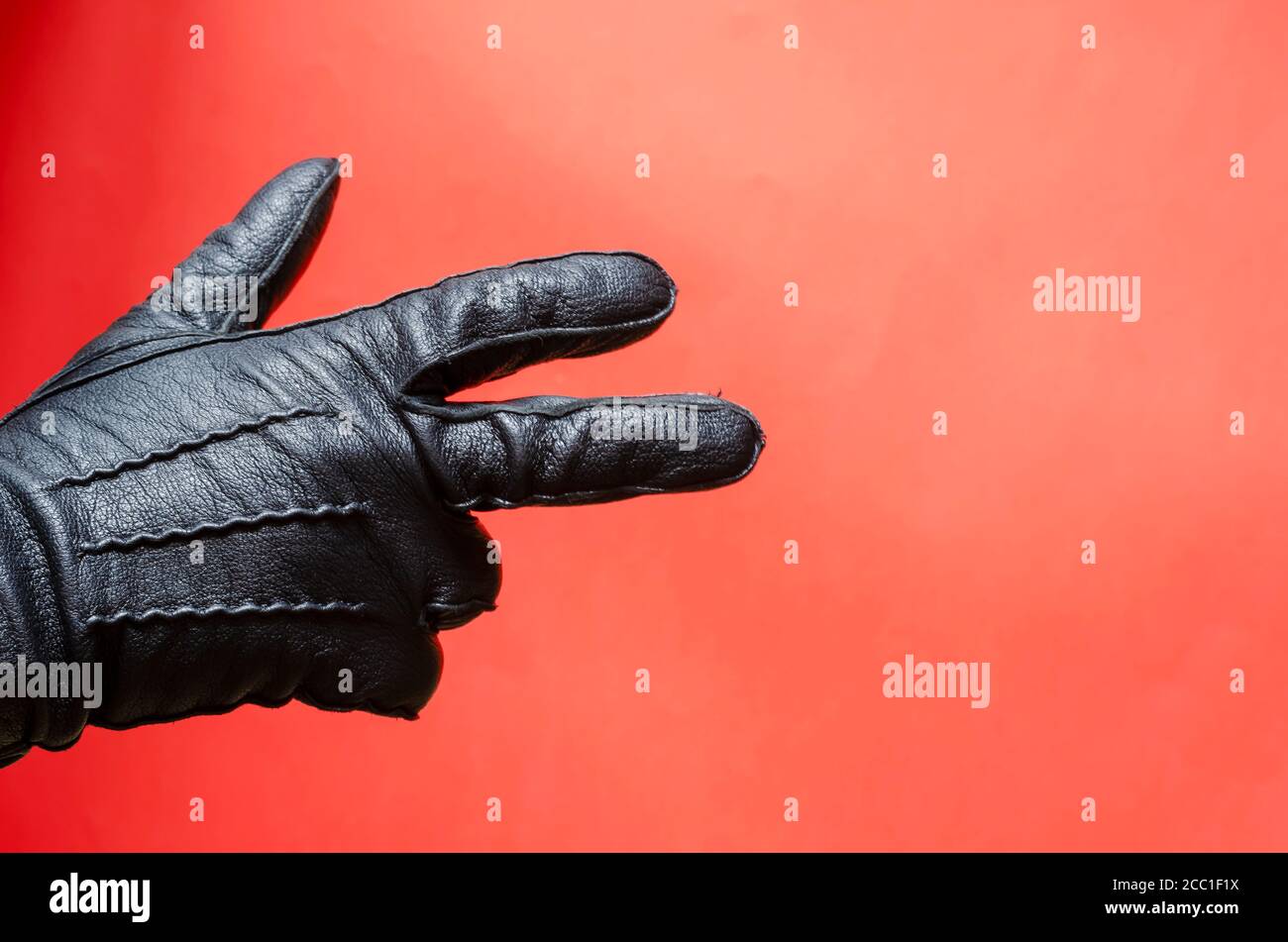Male hand in leather glove gestures against coral background. Man shows ...