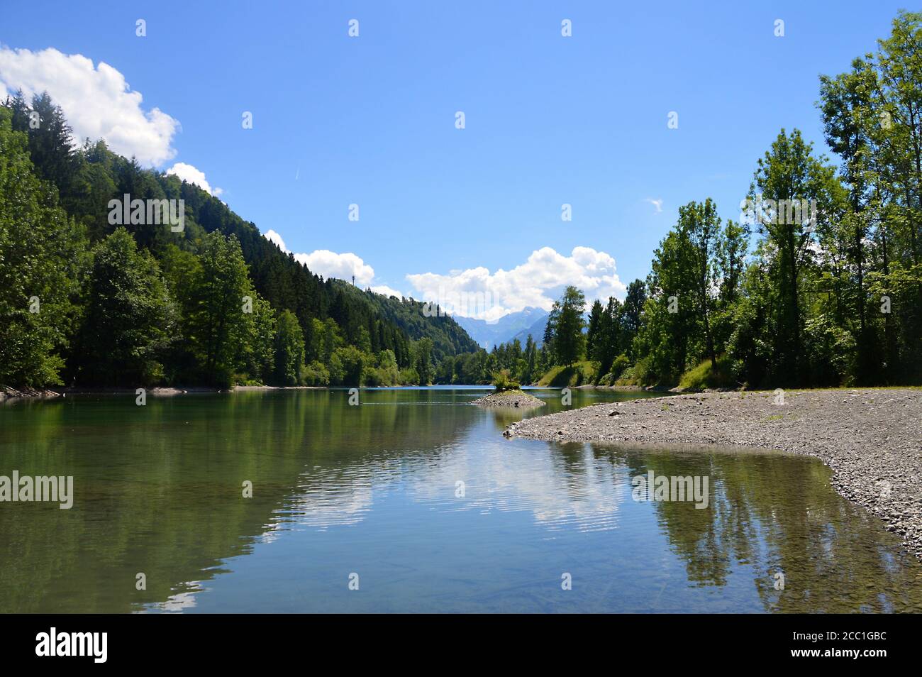 Closeup shot of a lake with shore and trees on the side and blue sky on ...